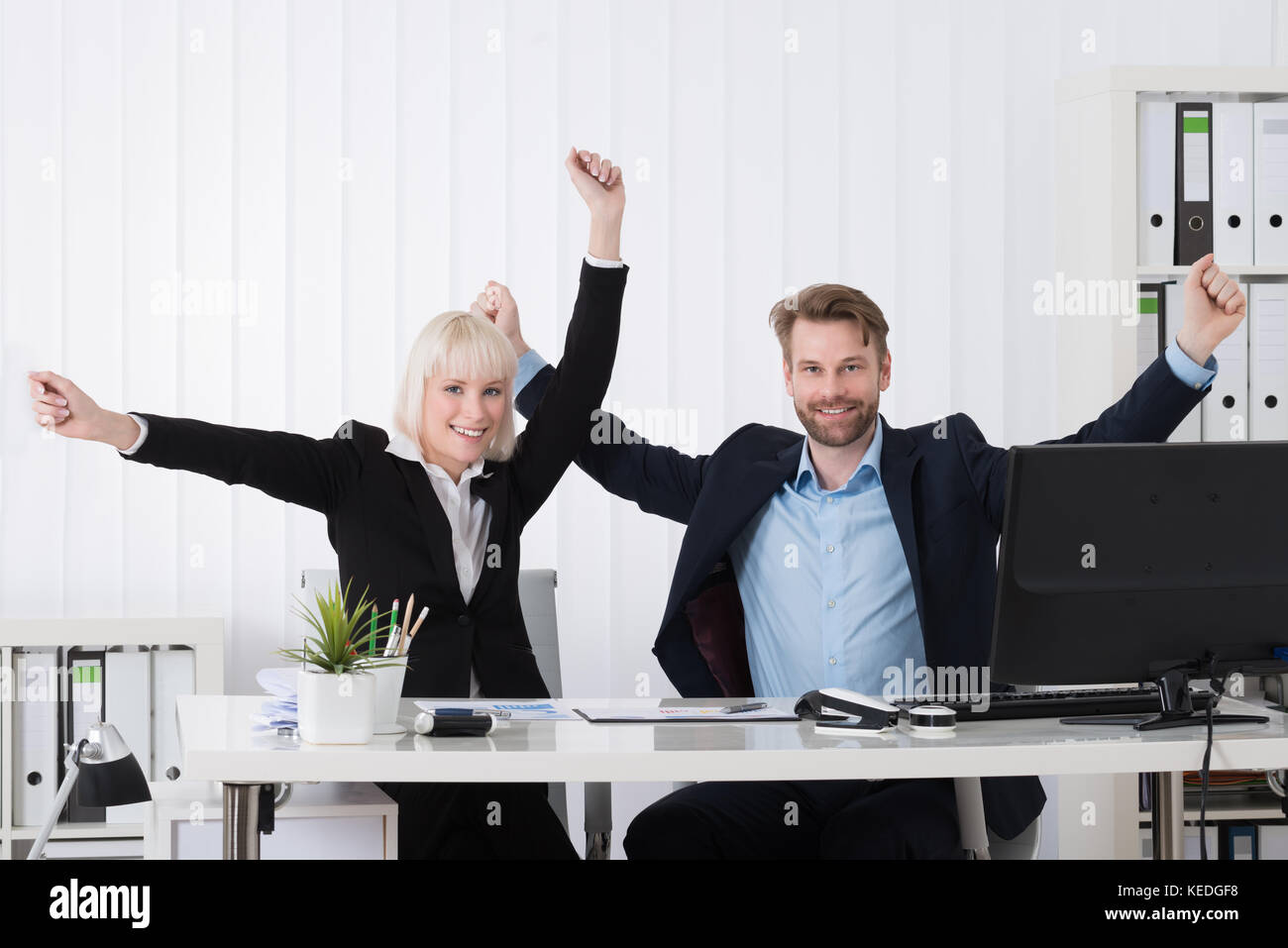 Two Happy Businesspeople Raising Hands In Office Stock Photo - Alamy