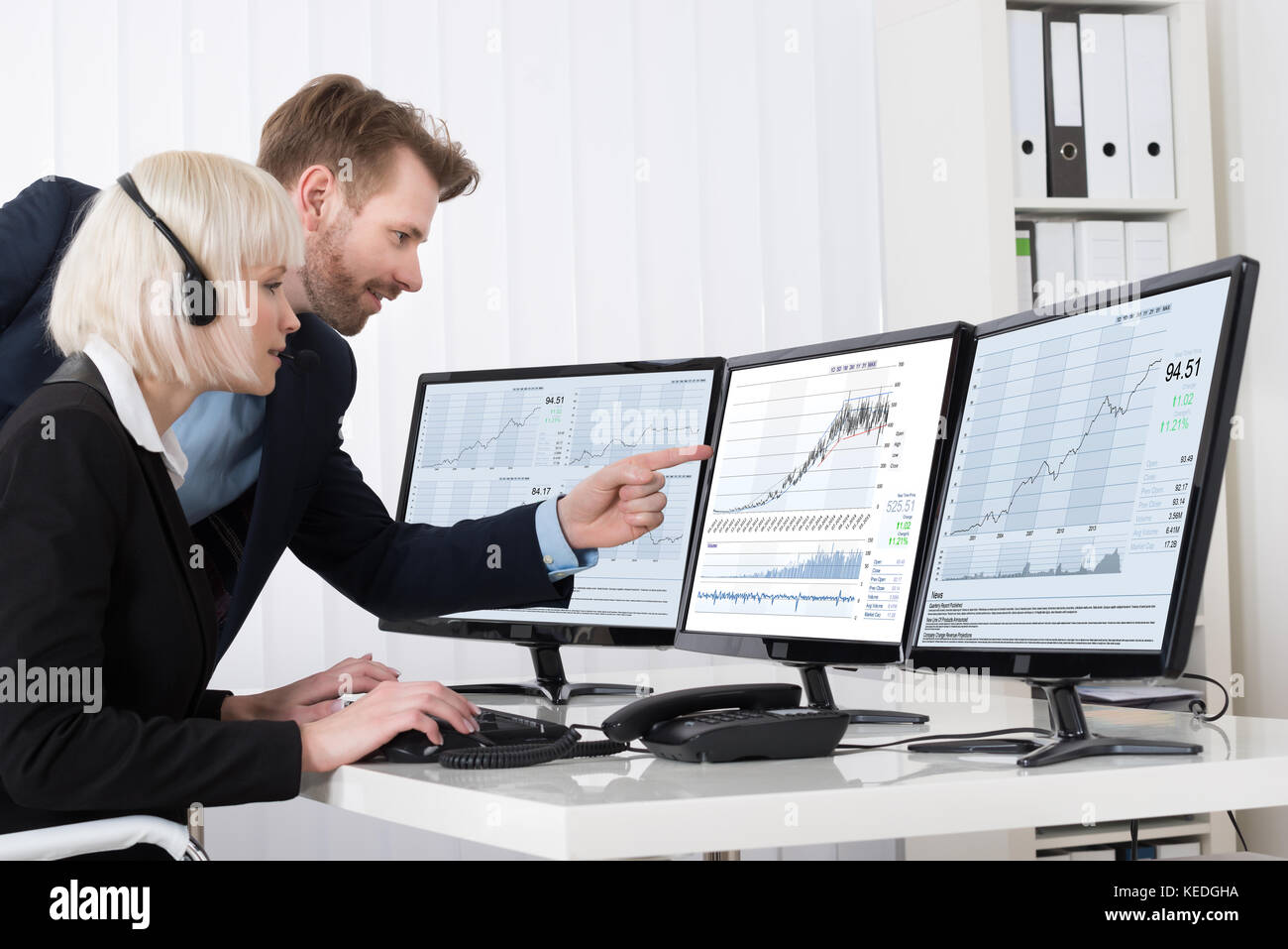 Two Businesspeople Analyzing Stock Charts On Multiple Computers Stock ...