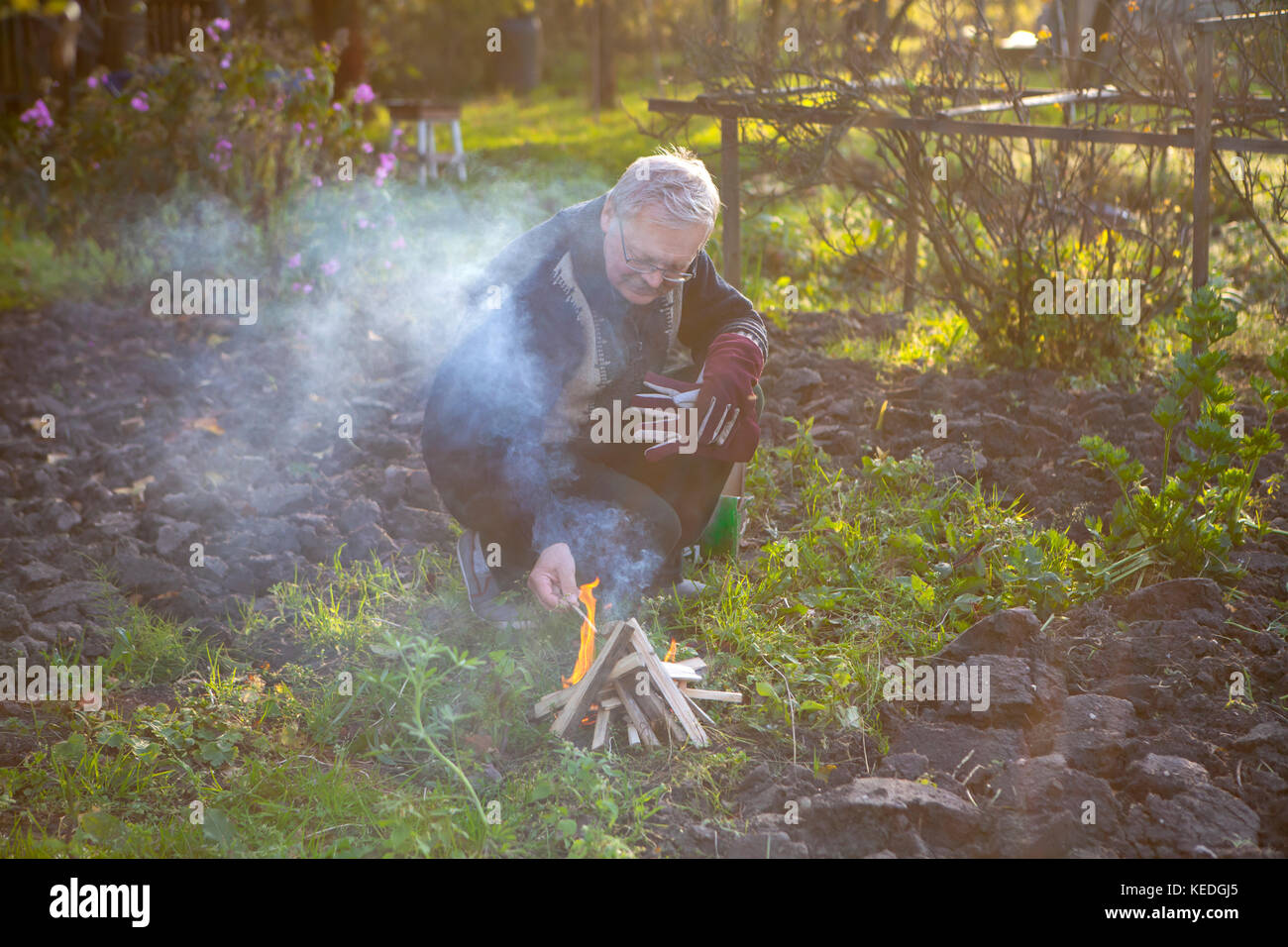Senior man making a bonfire in the garden Stock Photo - Alamy