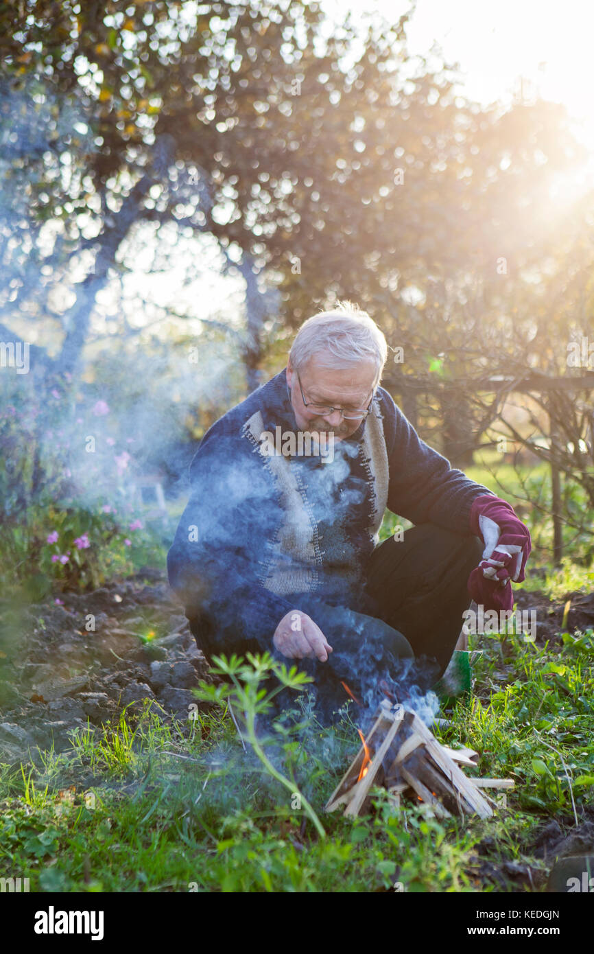 Senior man making a bonfire in the garden Stock Photo - Alamy