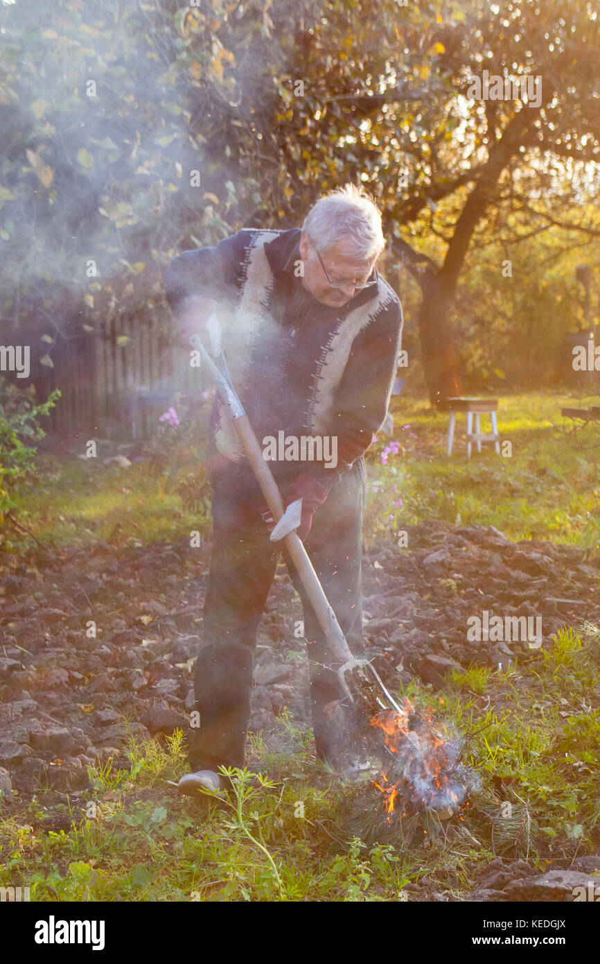 Senior man making a bonfire in the garden Stock Photo - Alamy