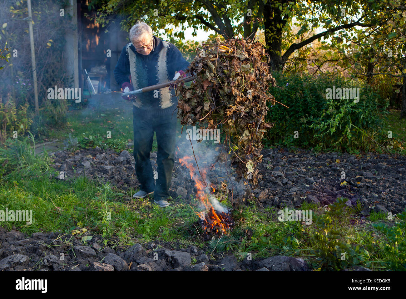 Senior man making a bonfire in the garden Stock Photo - Alamy