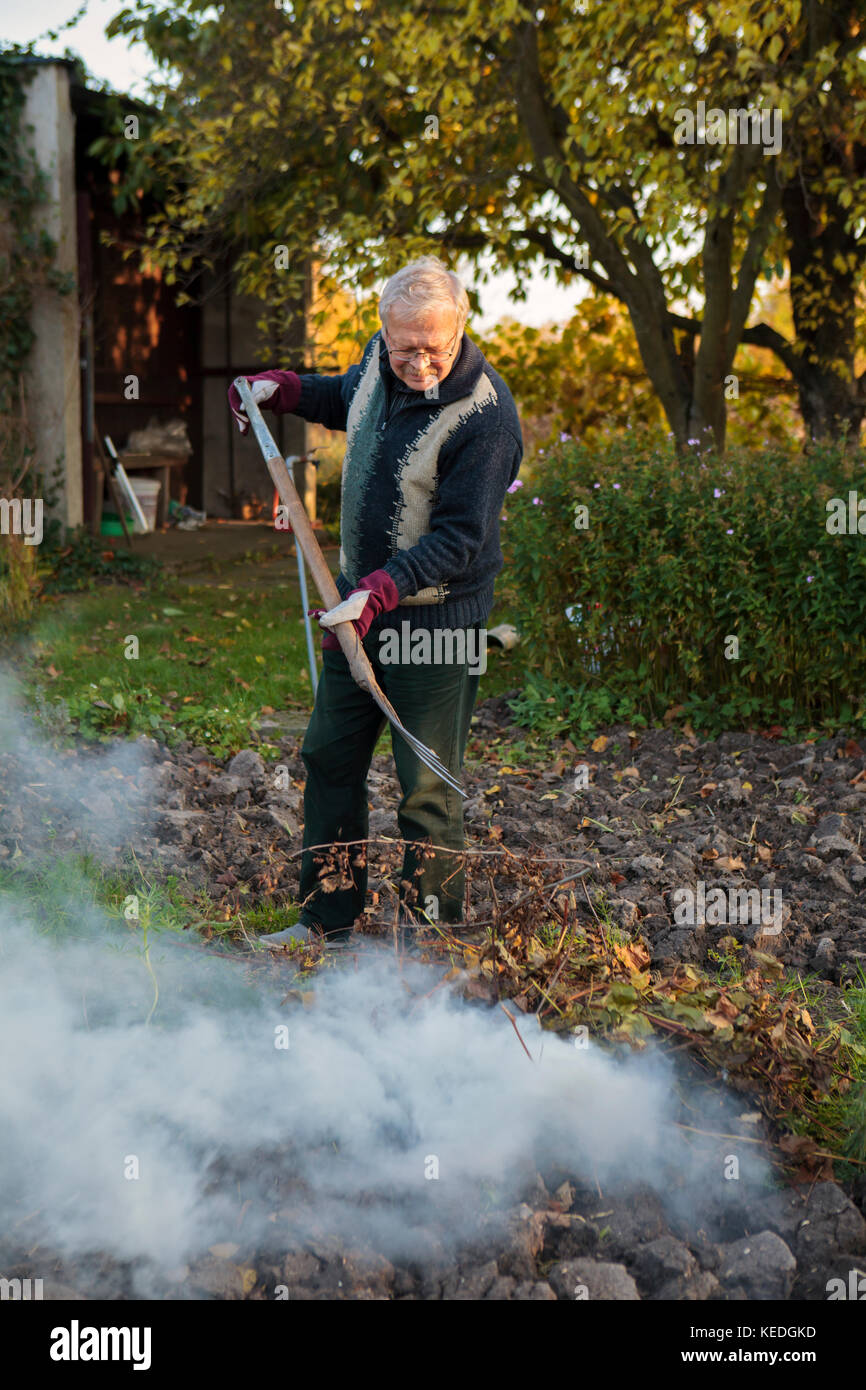 Senior man making a bonfire in the garden Stock Photo - Alamy