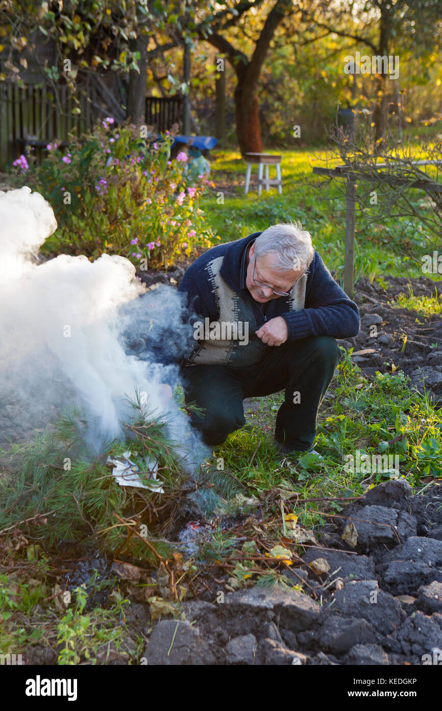 Senior man making a bonfire in the garden Stock Photo - Alamy