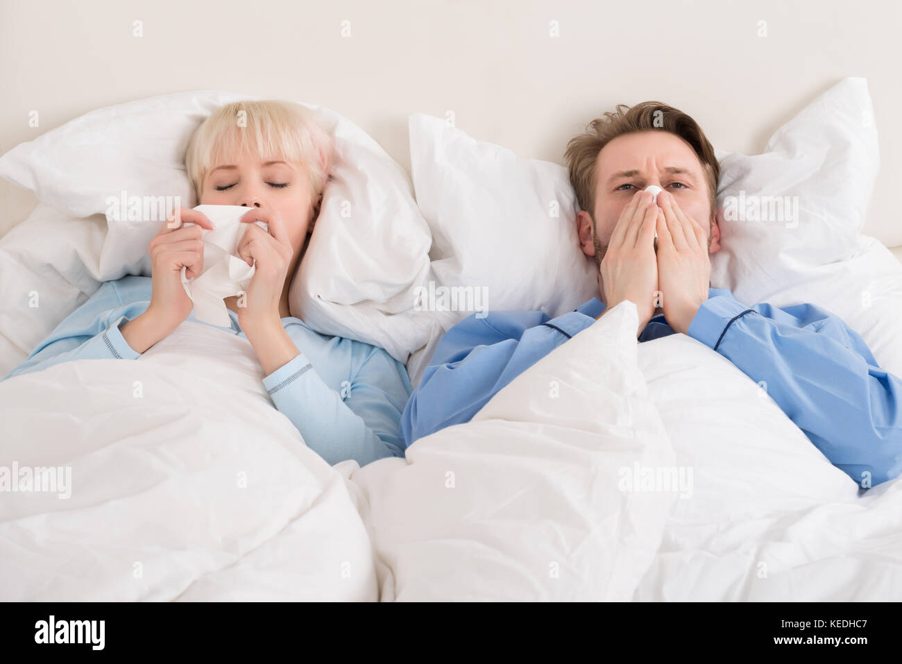 Young Couple Blowing Their Nose While Lying In Bed At Home Stock Photo ...