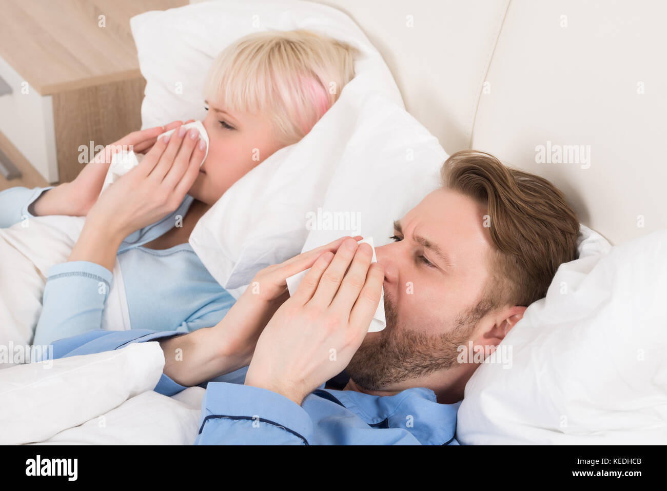 Young Couple Blowing Their Nose While Lying In Bed At Home Stock Photo ...