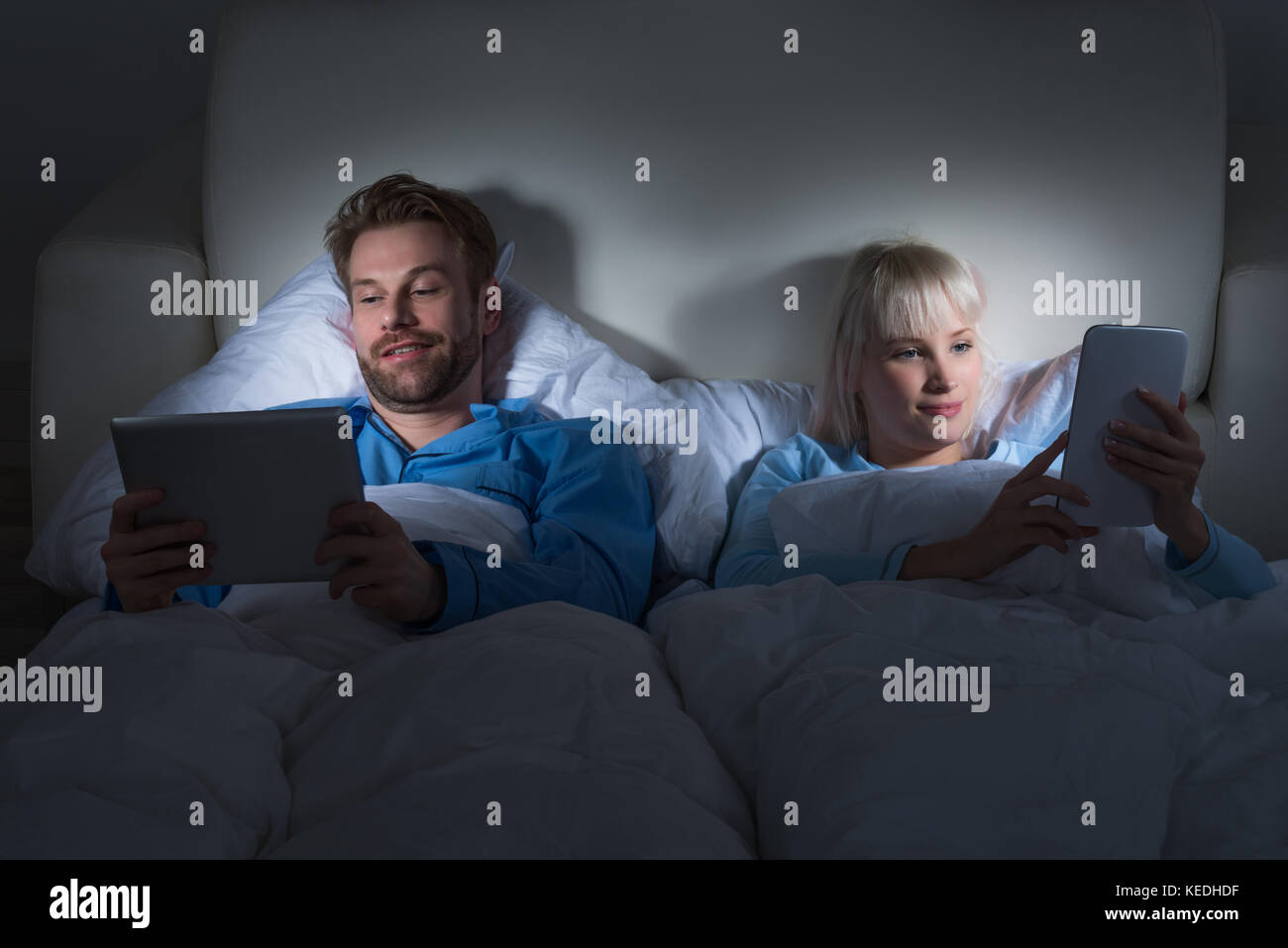 Young Happy Couple Lying In Bed Using Digital Tablets Stock Photo - Alamy
