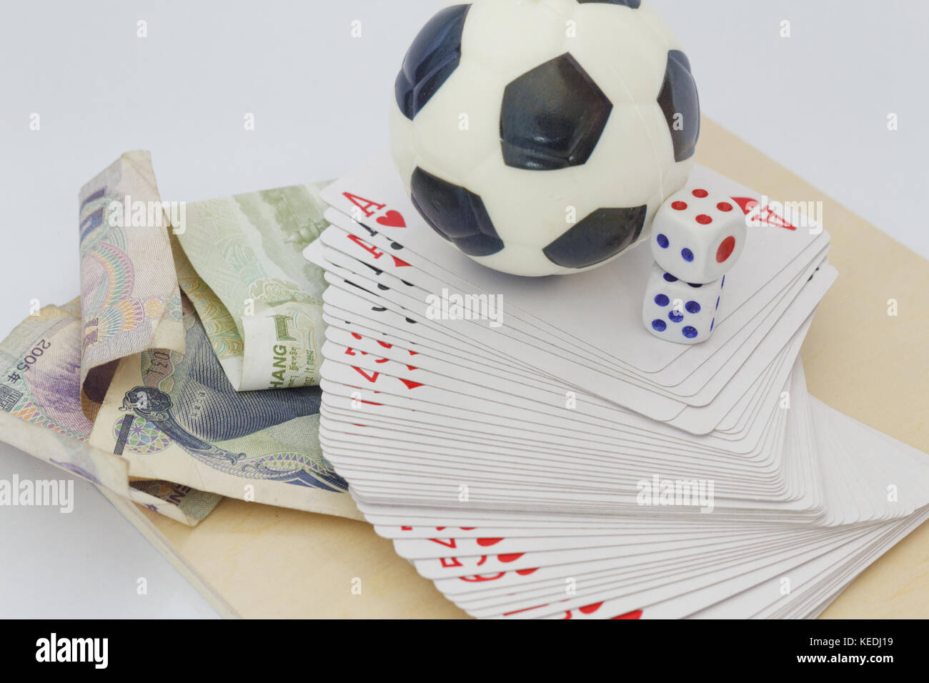 Mini soccer ball on top of playing cards with dices and money in ...