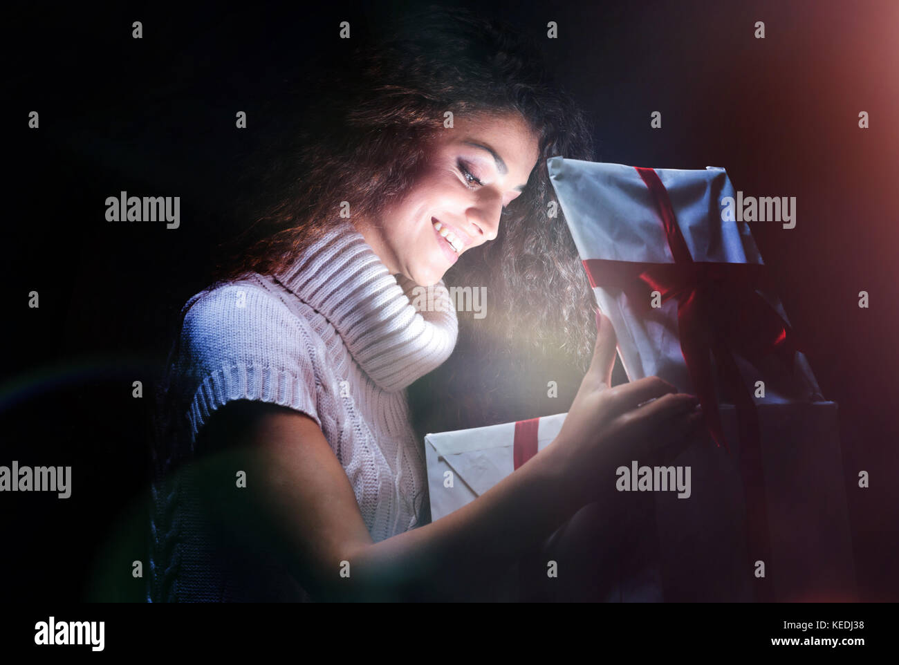 Excited cheerful attractive young woman opening gift over black Stock ...