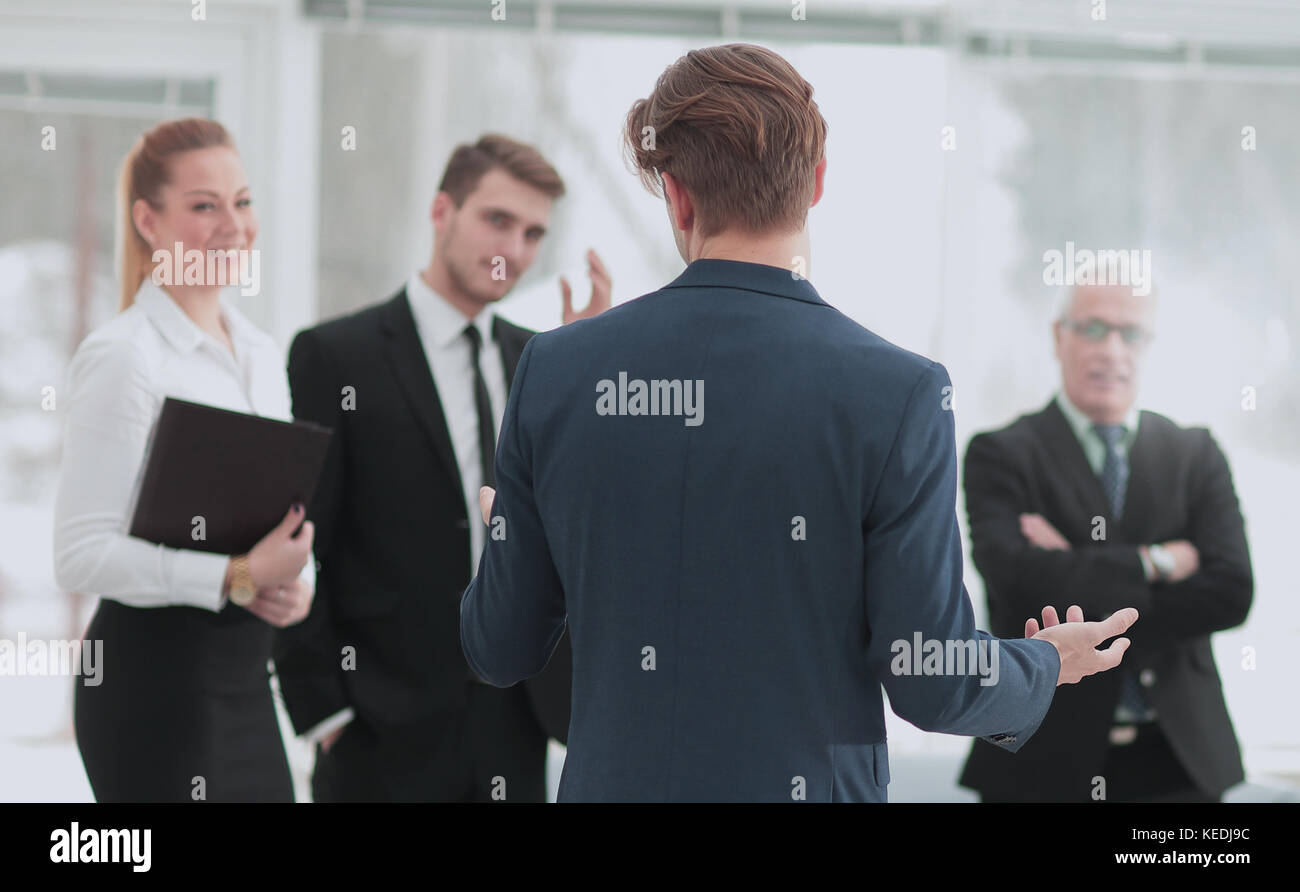 Successful business man standing with his staff in background at Stock ...