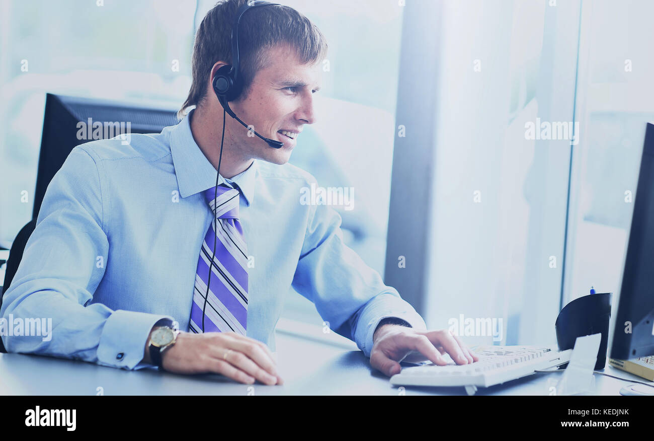 Happy young man working at callcenter, using headset Stock Photo - Alamy