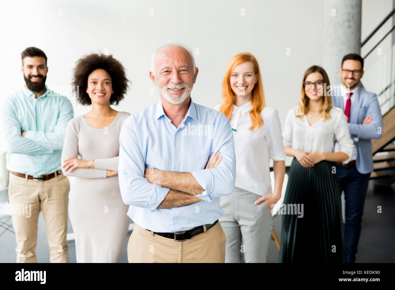 Young business people with senior colleague standing in the office ...
