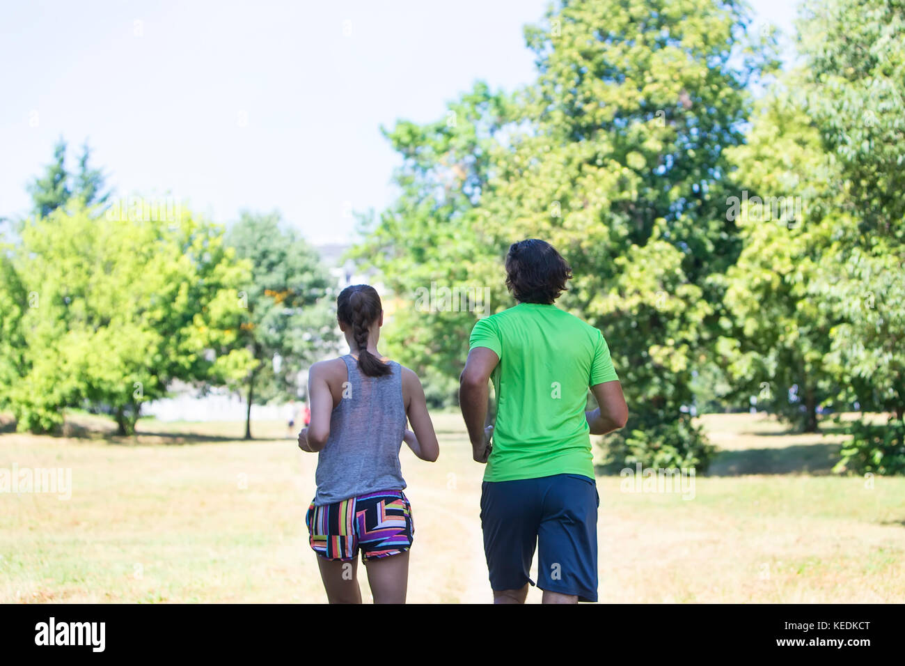 Back view at healthy, fit and sportive couple running in park at summer ...