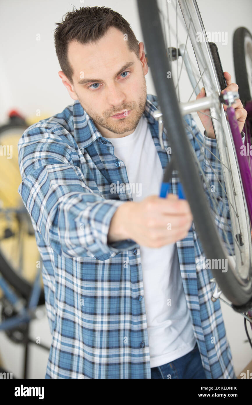 man fixing wheel of bike in his workshop Stock Photo - Alamy