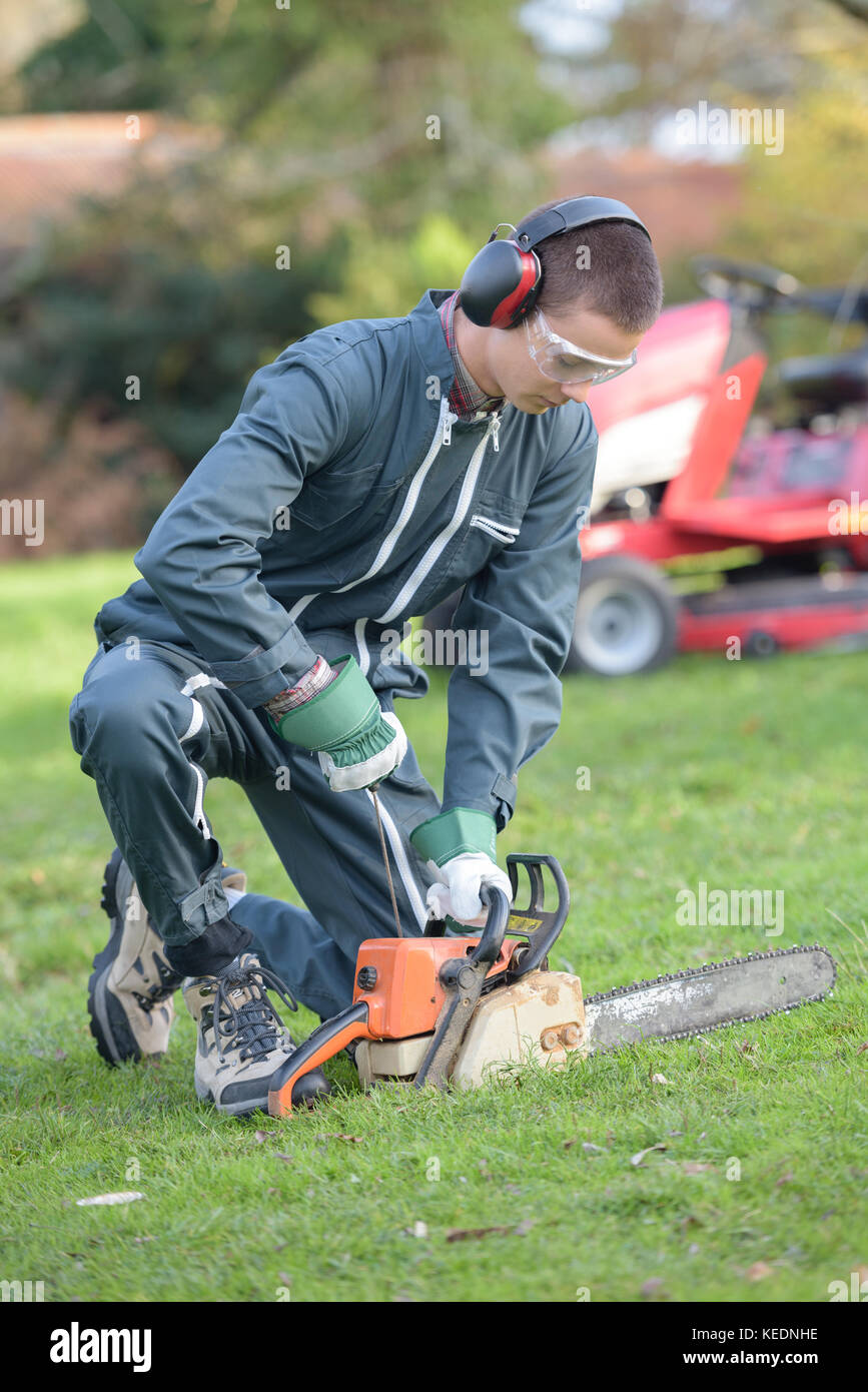 Young man starting chainsaw Stock Photo - Alamy