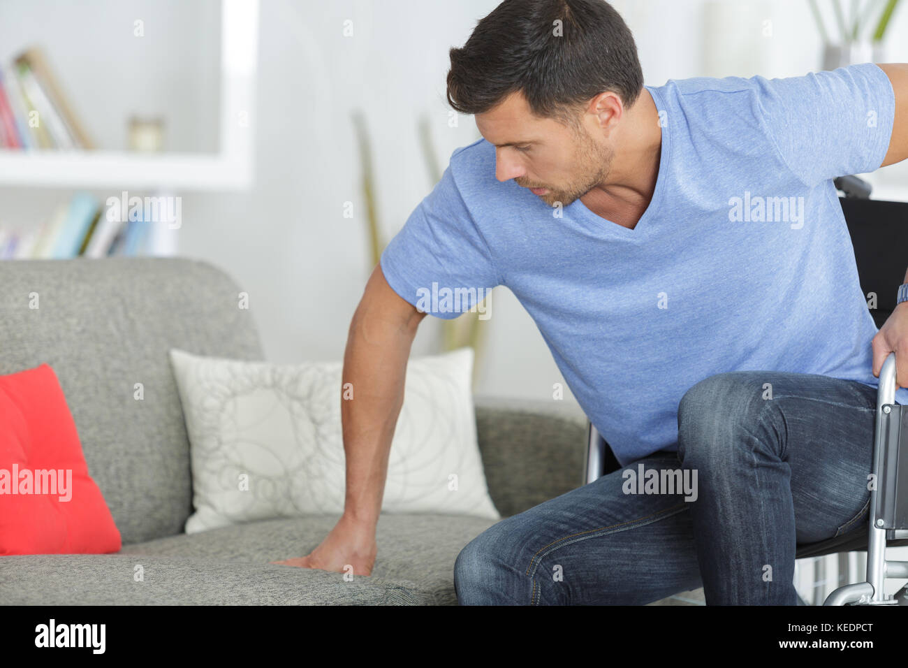 disabled man trying to sit on sofa Stock Photo - Alamy