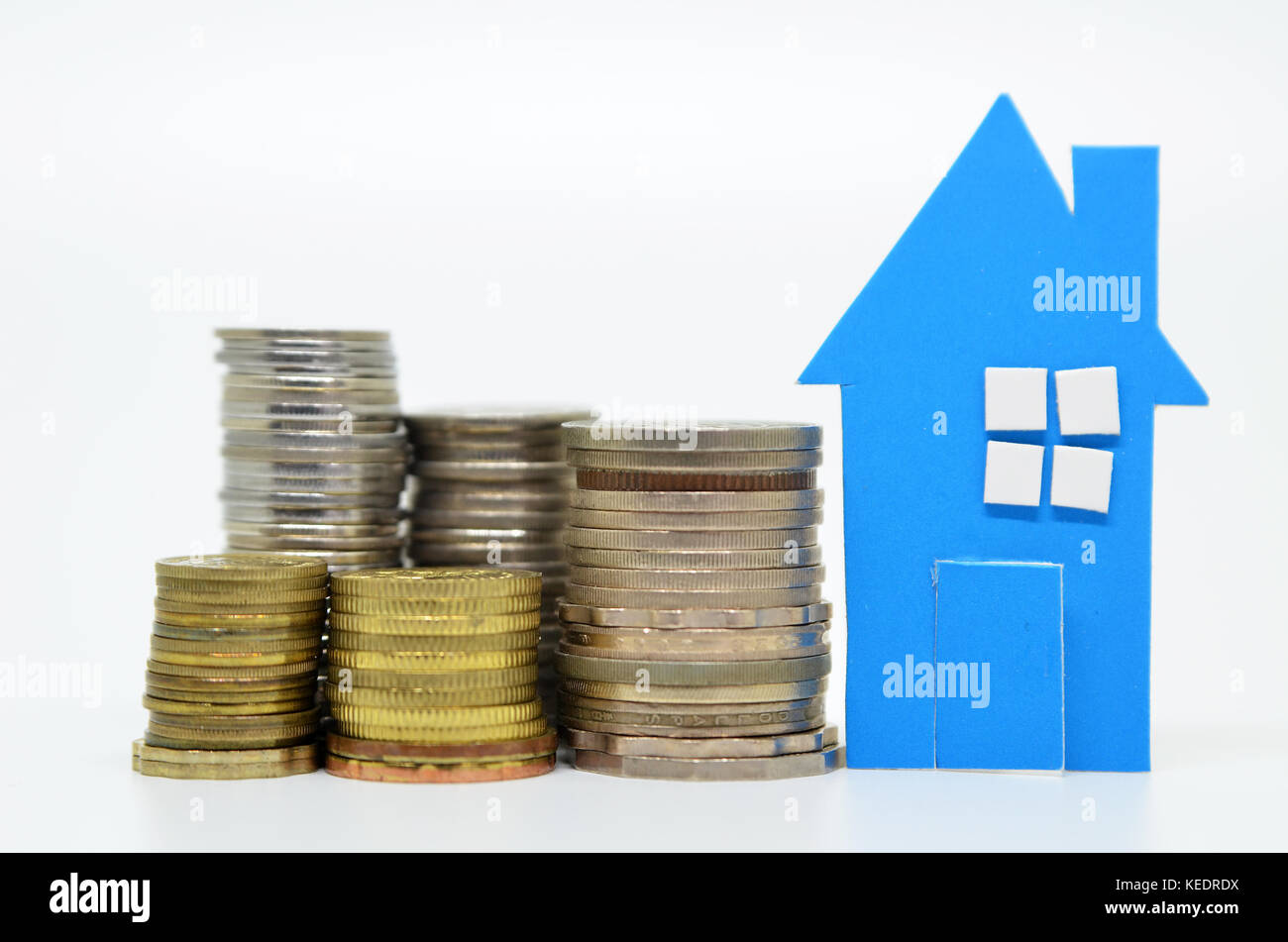 Blue paper house model and stacks of coins Stock Photo - Alamy