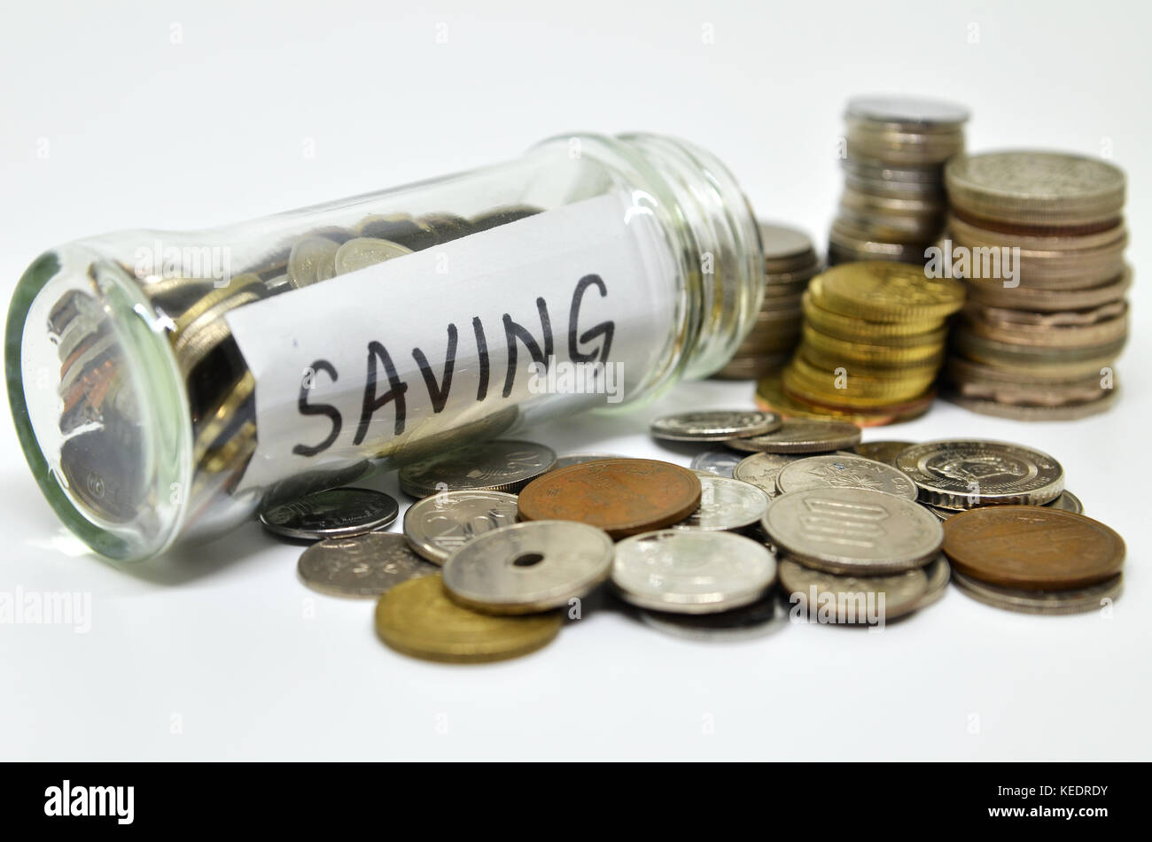 Saving lable in a glass jar with coins spilling out isolated on white ...