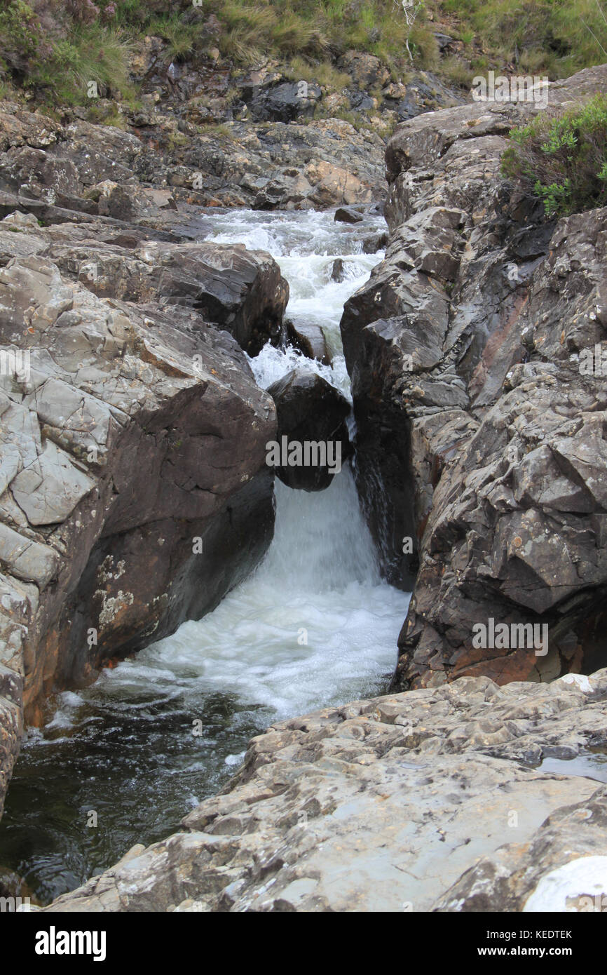 A rock wedged between two stone faces with water flowing against it ...