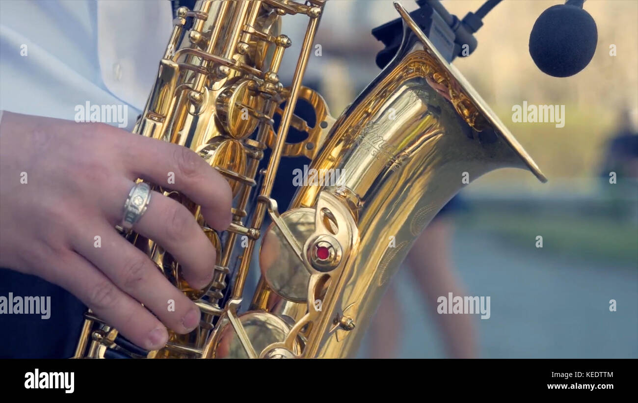 Young man with saxophone outside near the old painted wall. Young ...