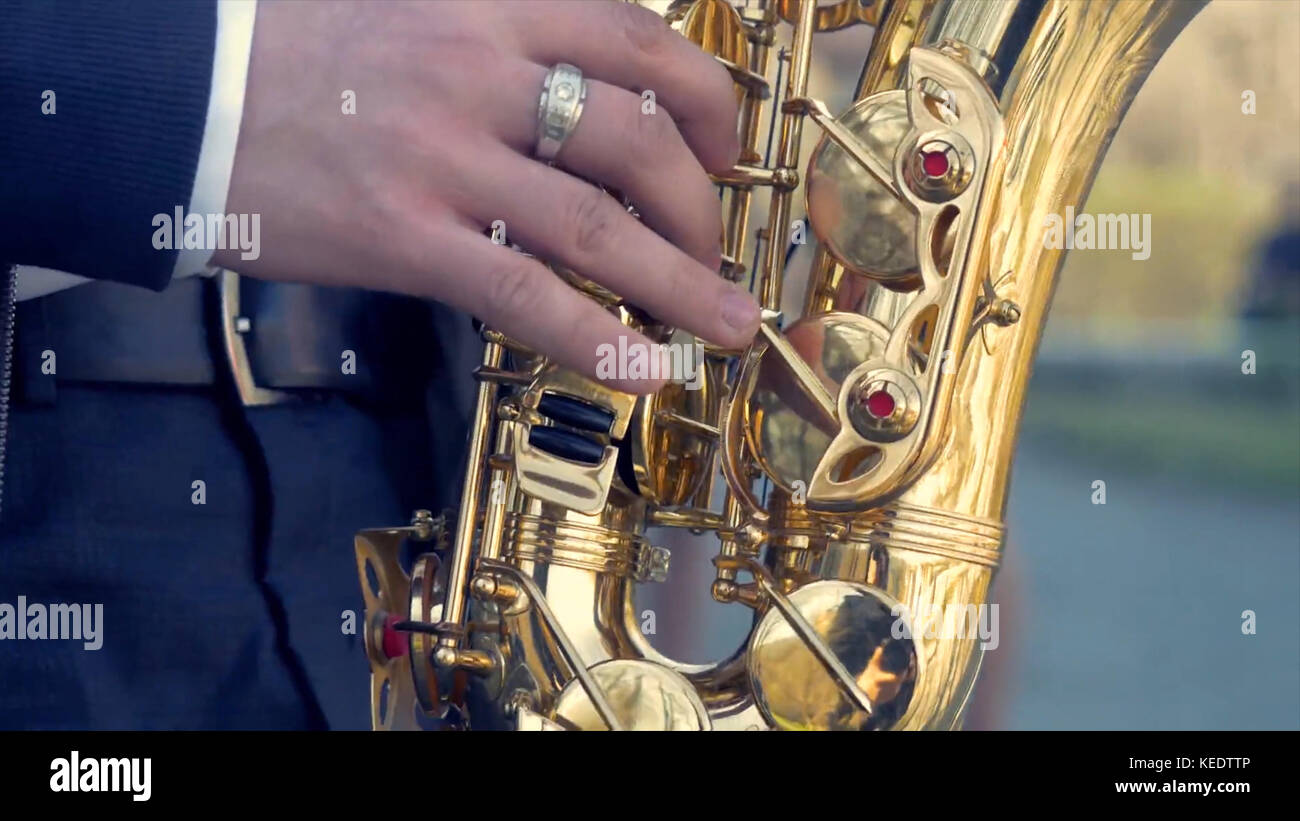 Young man with saxophone outside near the old painted wall. Young ...