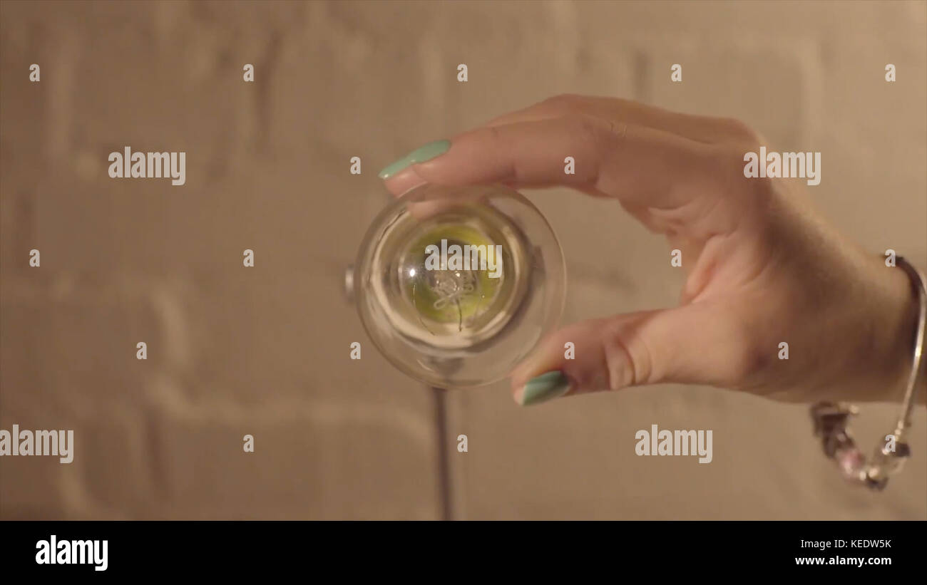 Female hand unscrews a light bulb. Woman unscrews a light bulb to light ...