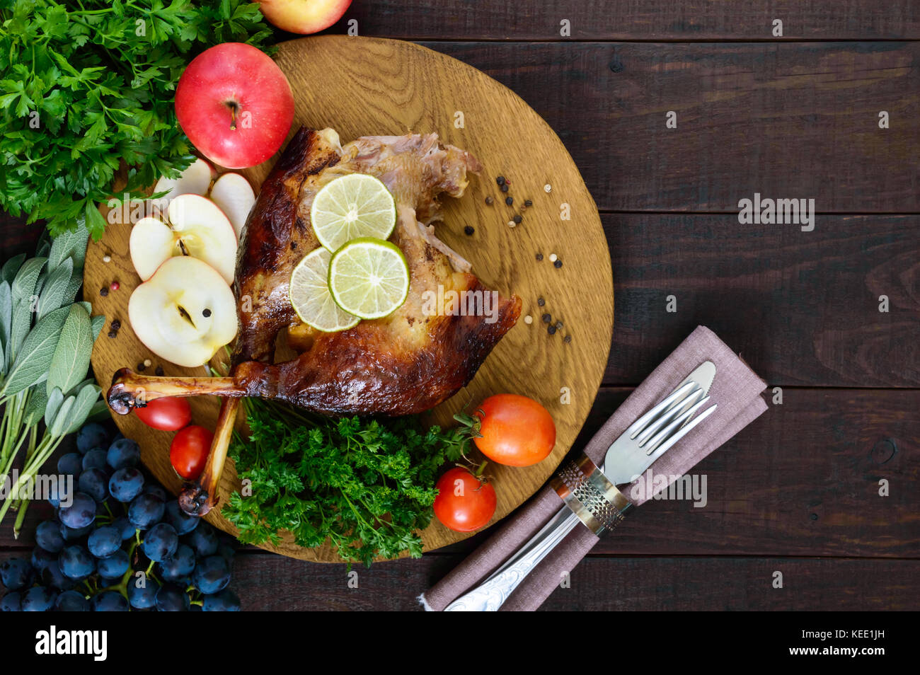 Baked goose legs, served with apples, vegetables, grapes, greens on a ...