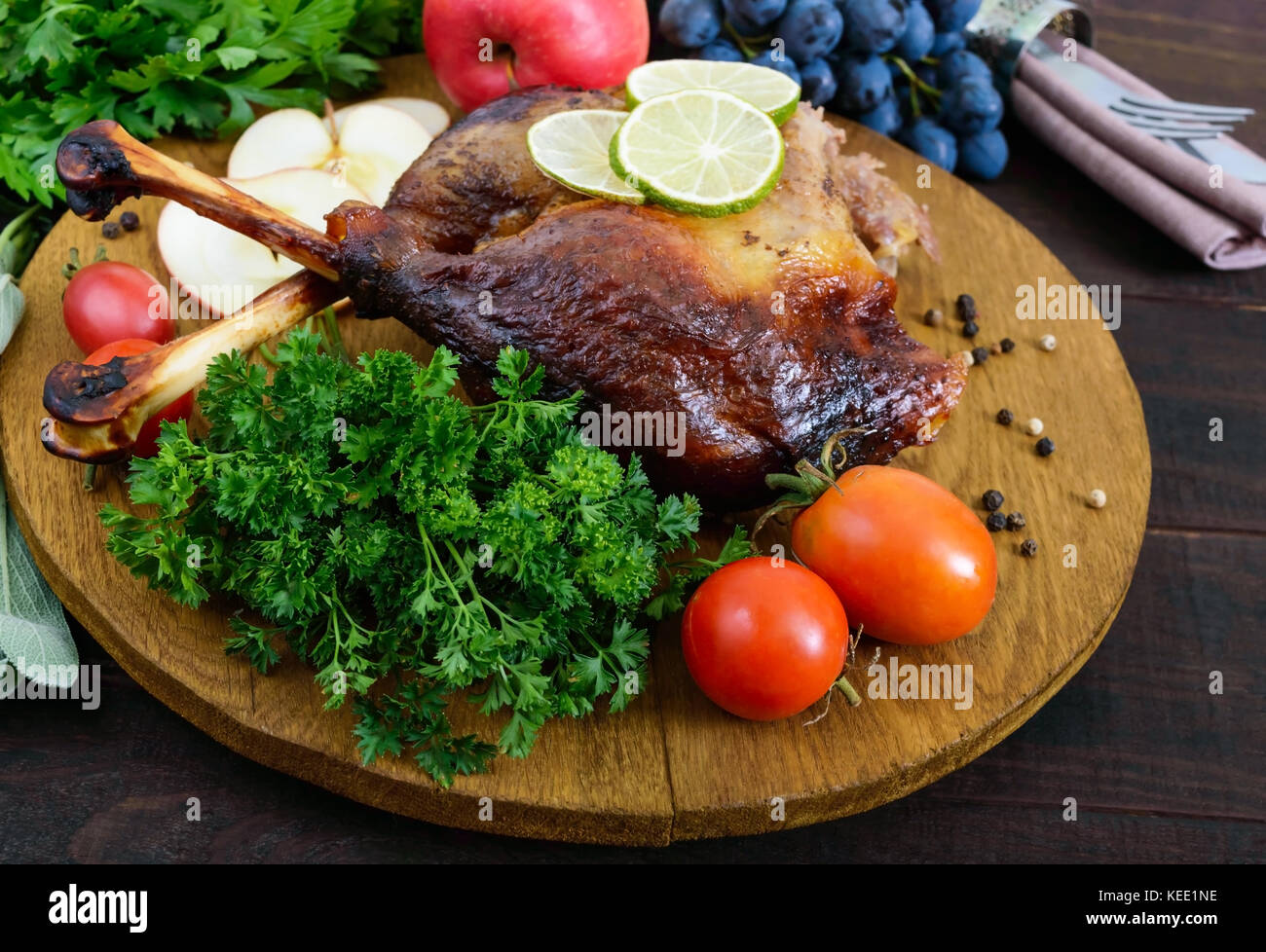 Baked goose legs, served with apples, vegetables, grapes, greens on a ...