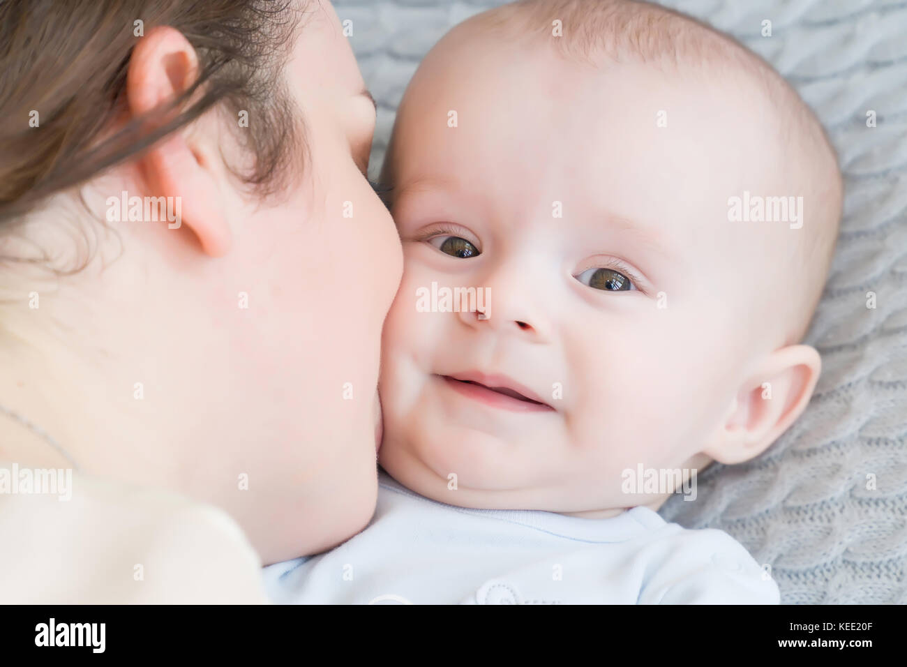 Close-up portrait of happy young mother hugging and kissing his sweet ...