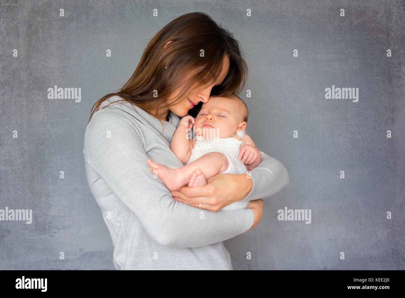 Young mother, caressing her newborn baby boy, holding him in her arms ...