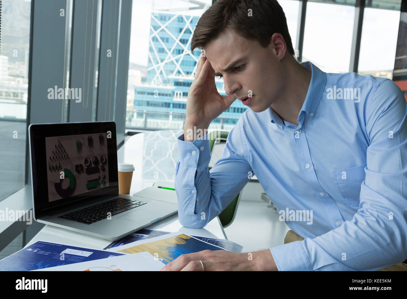 Depressed male executive sitting at desk in futuristic office Stock ...