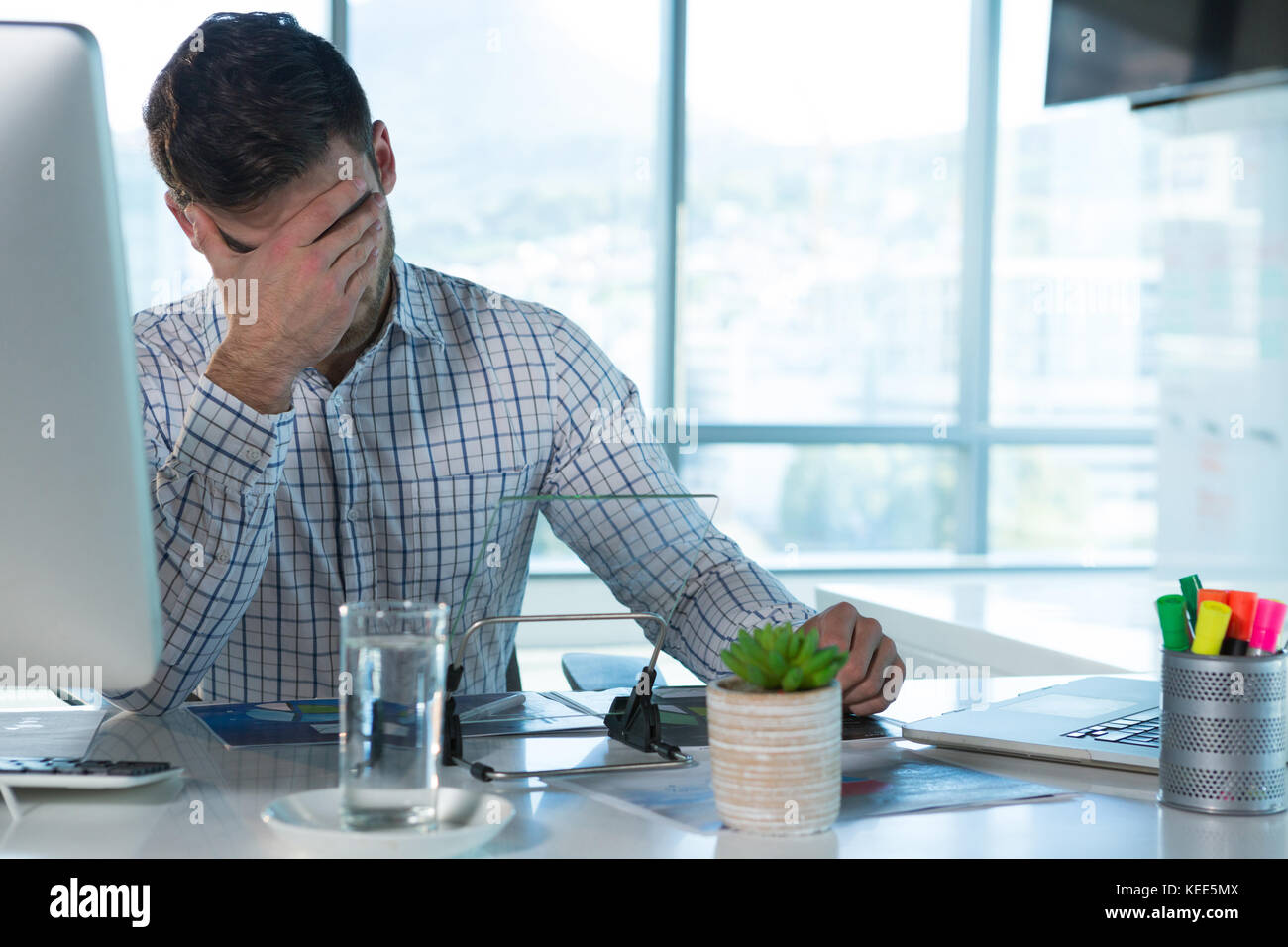Male executive suffering from headache at desk in office Stock Photo ...