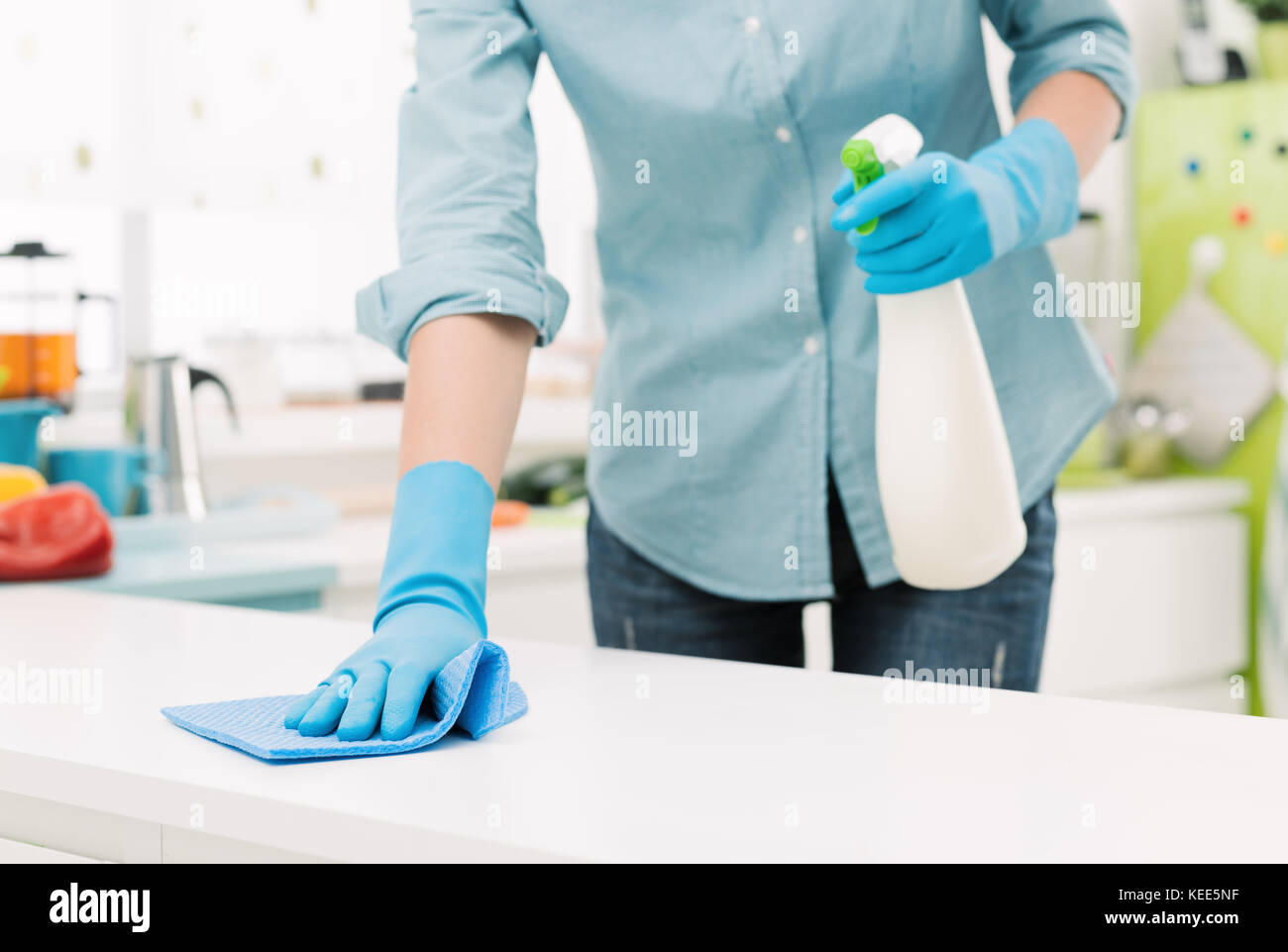 Woman cleaning and polishing the kitchen worktop with a spray detergent ...