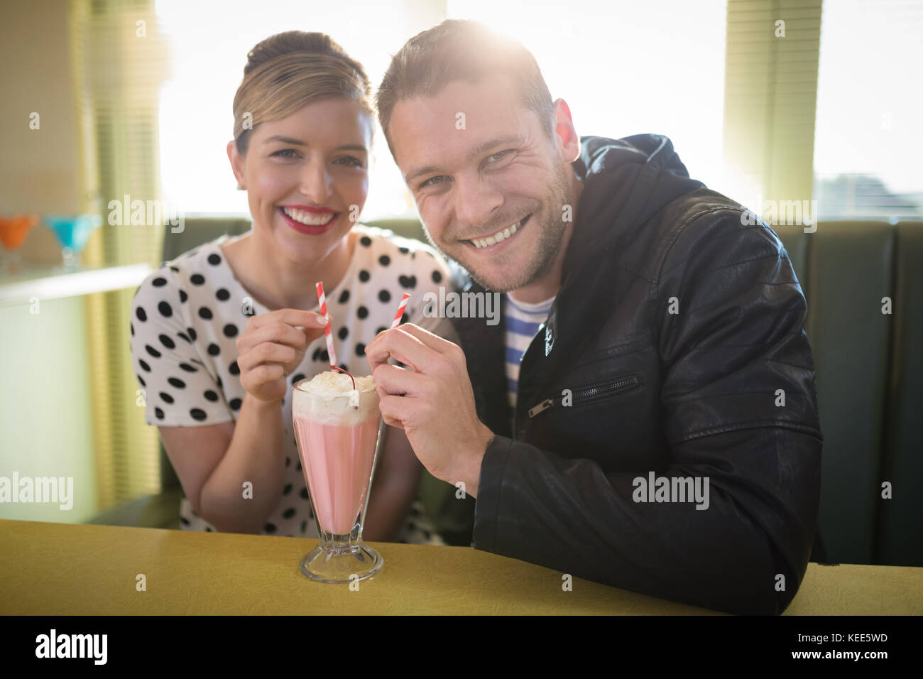 Young couple having milkshake in restaurant Stock Photo - Alamy
