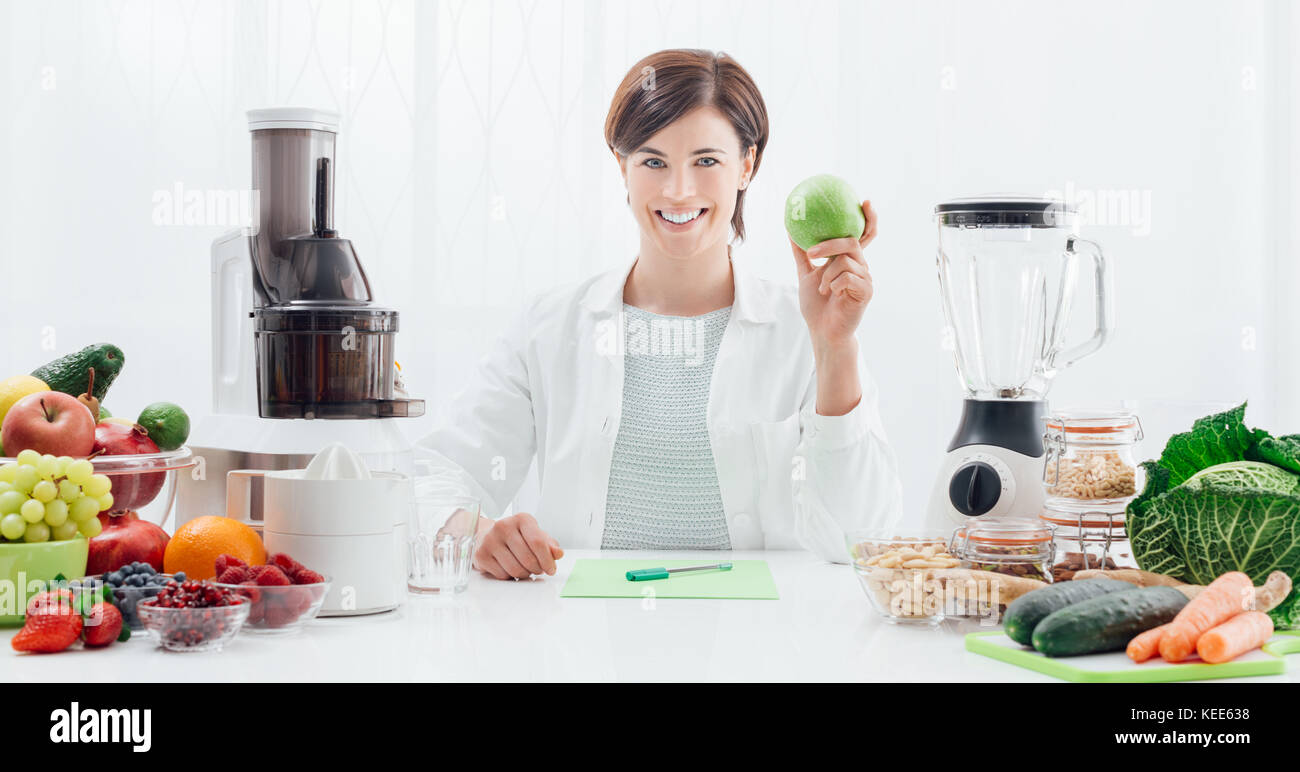 Smiling professional nutritionist holding an apple, she has healthy ...