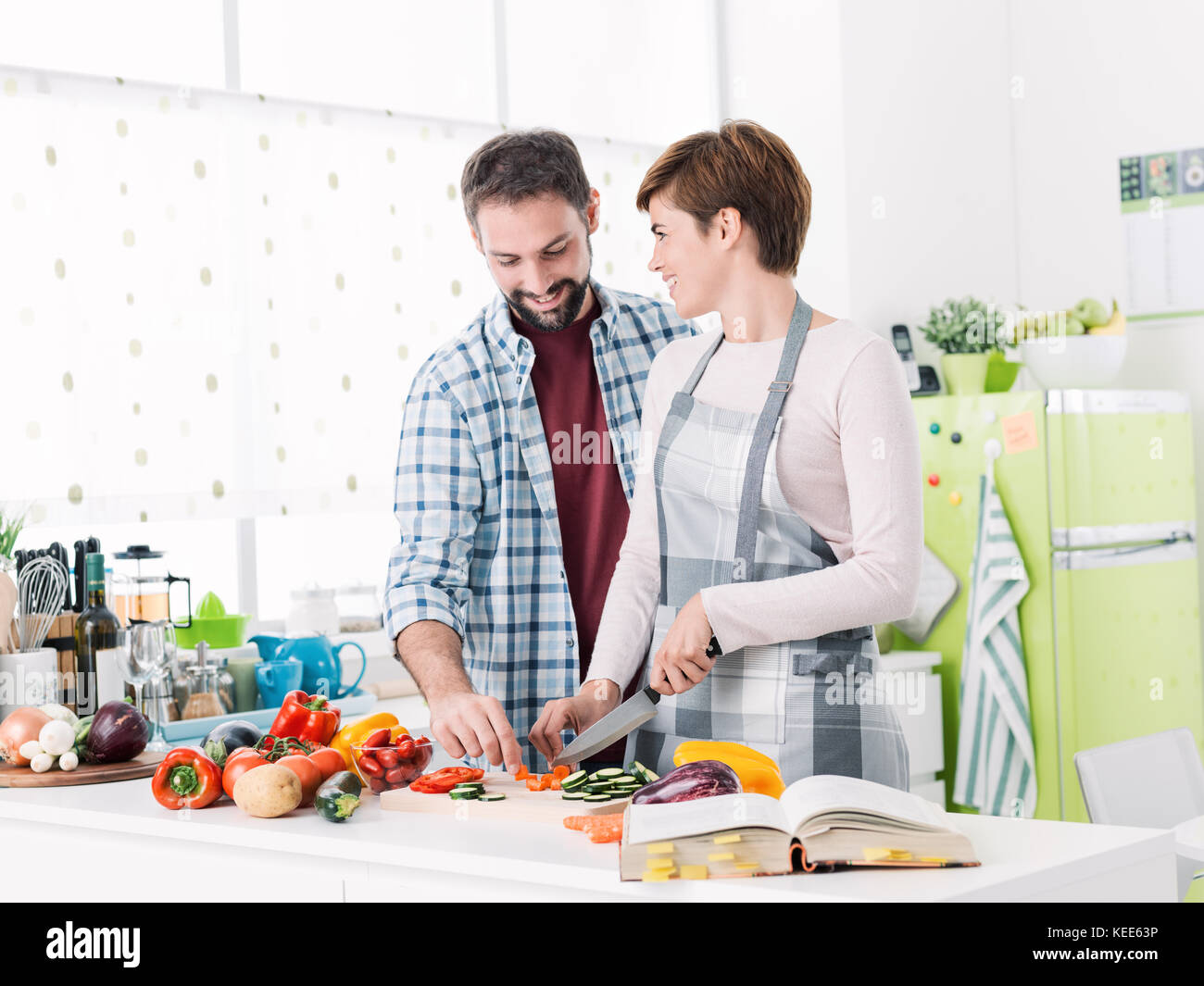 Romantic loving couple cooking together at home, the woman is slicing ...