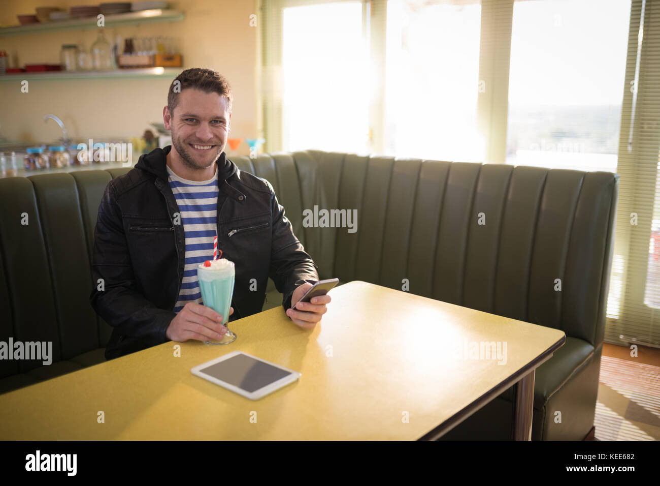 Young man having milkshake in restaurant Stock Photo - Alamy