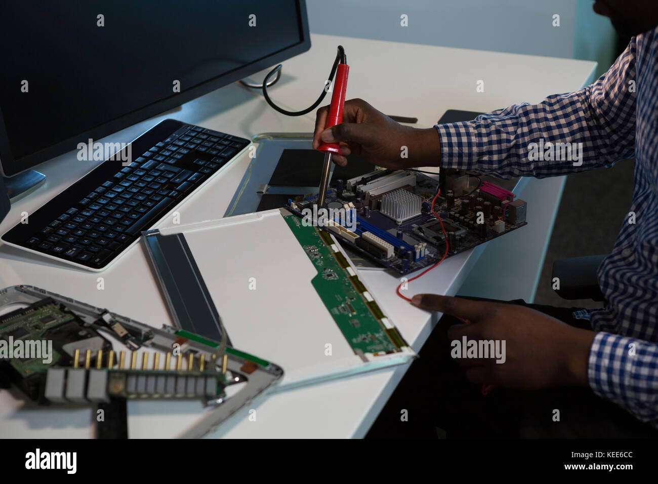 Computer engineer repairing motherboard at desk in office Stock Photo ...