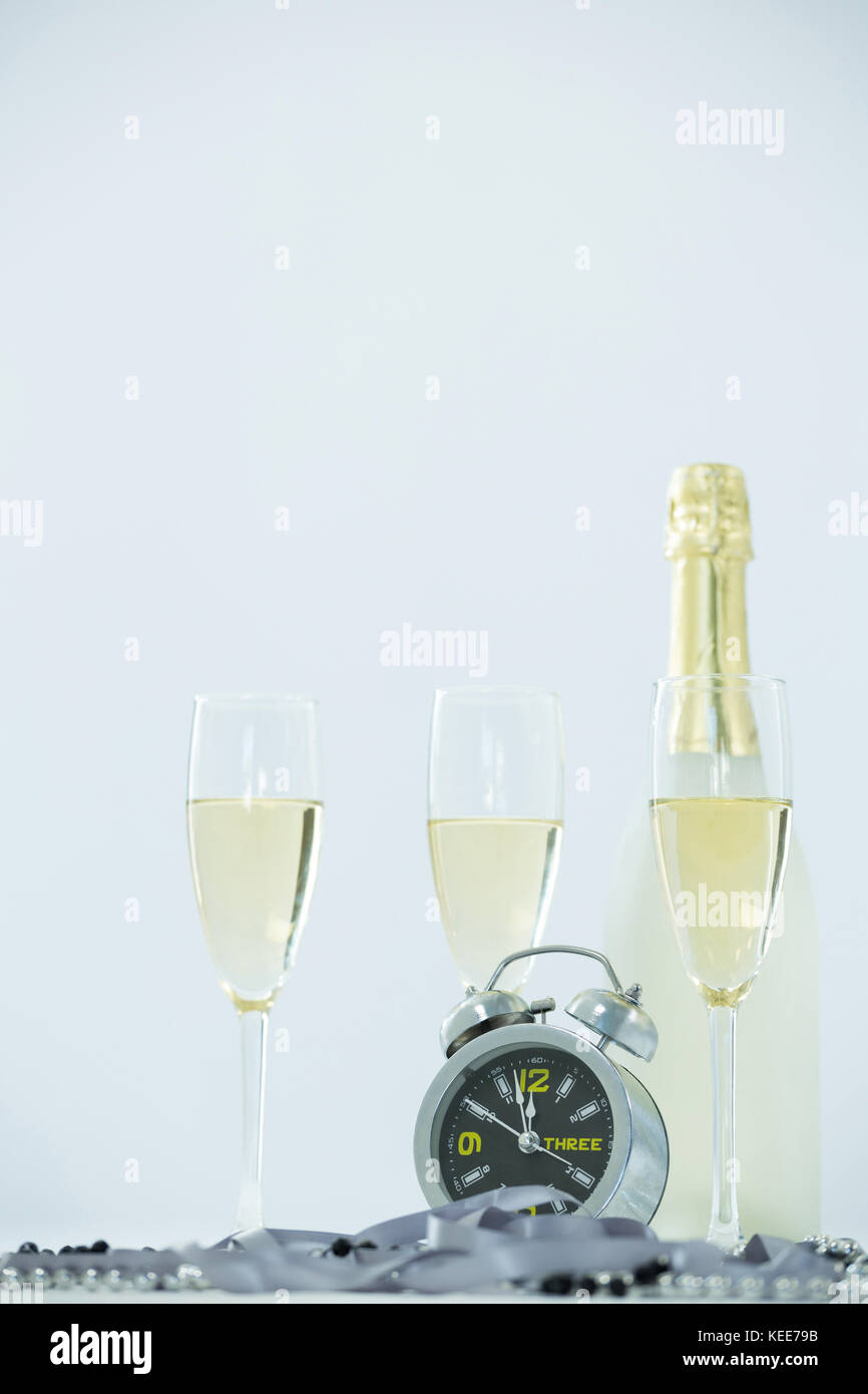 Close-up of champagne with alarm clock and glass on white background ...