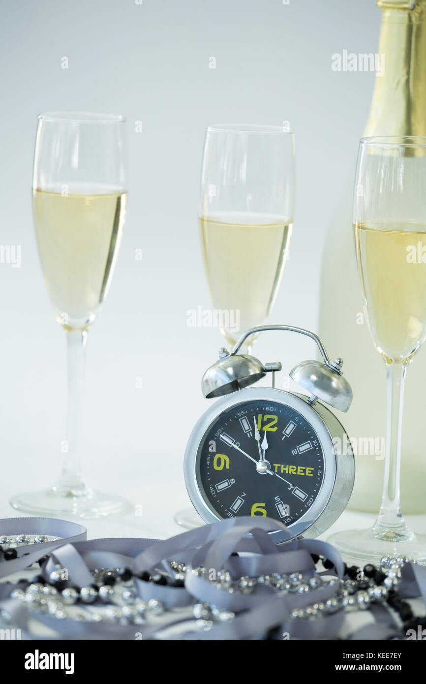 Close-up of champagne with alarm clock and glass on white background ...