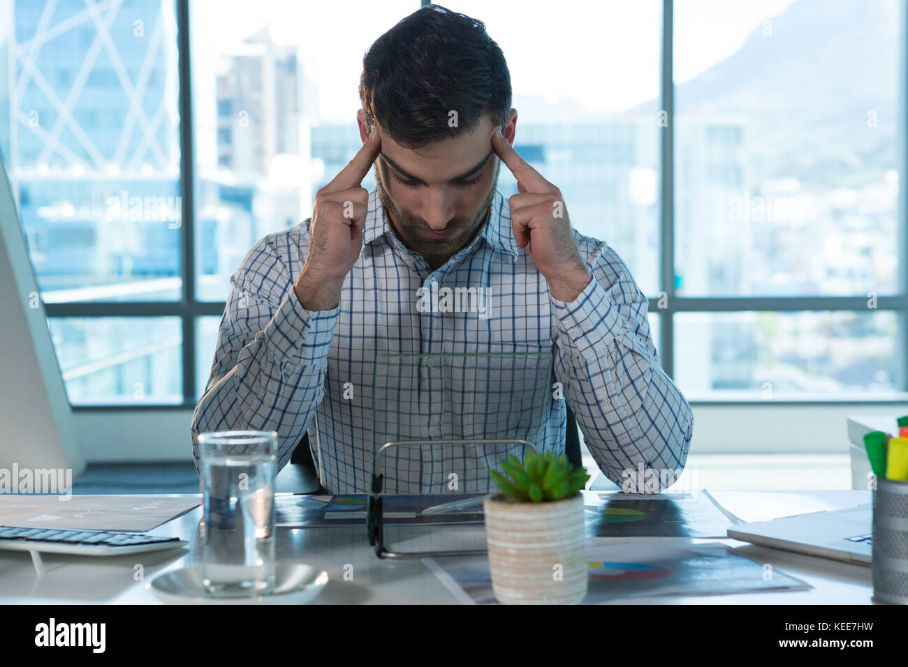 Male executive suffering from headache at desk in office Stock Photo ...