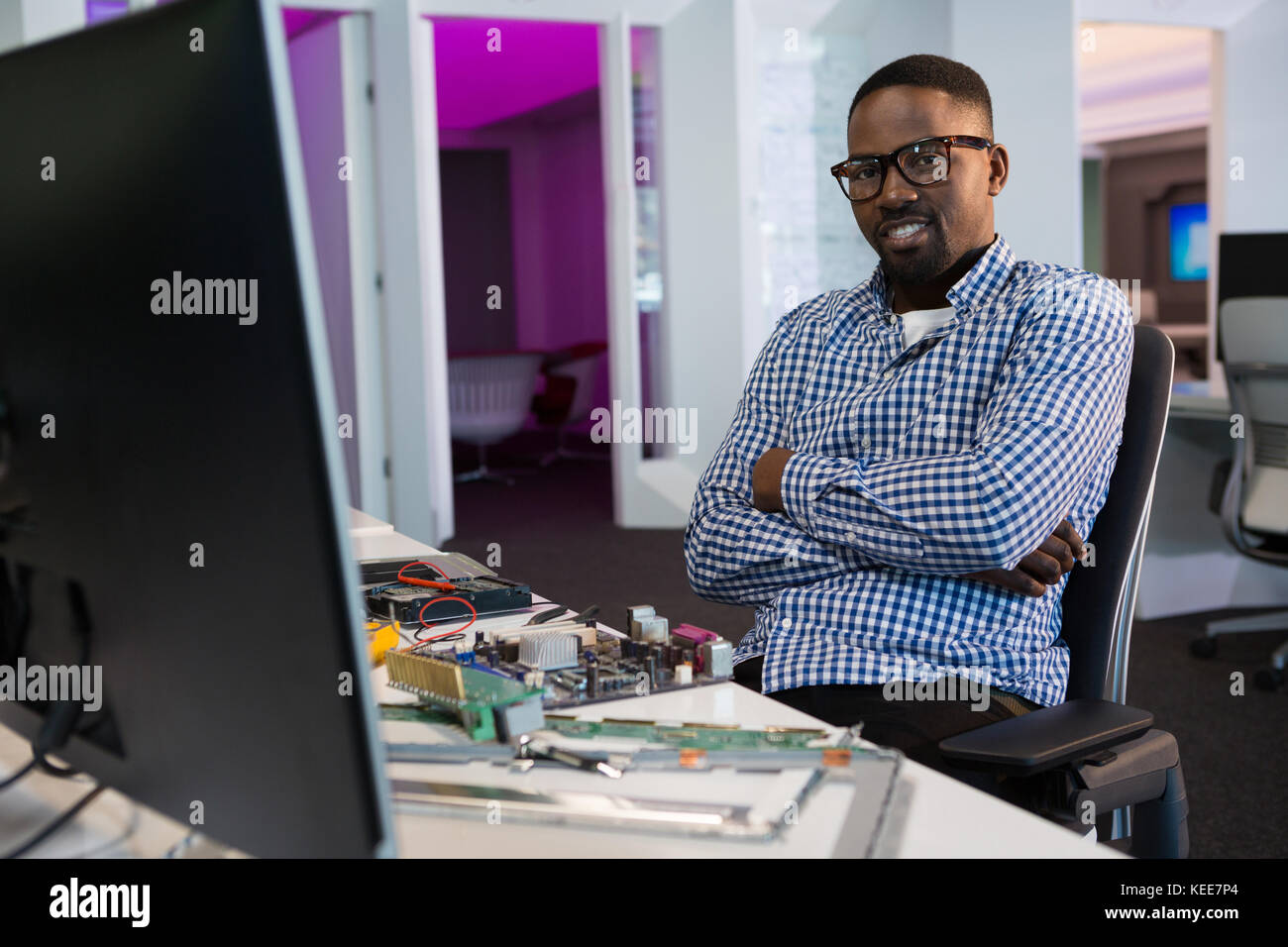 Portrait of computer engineer repairing motherboard at desk in office ...