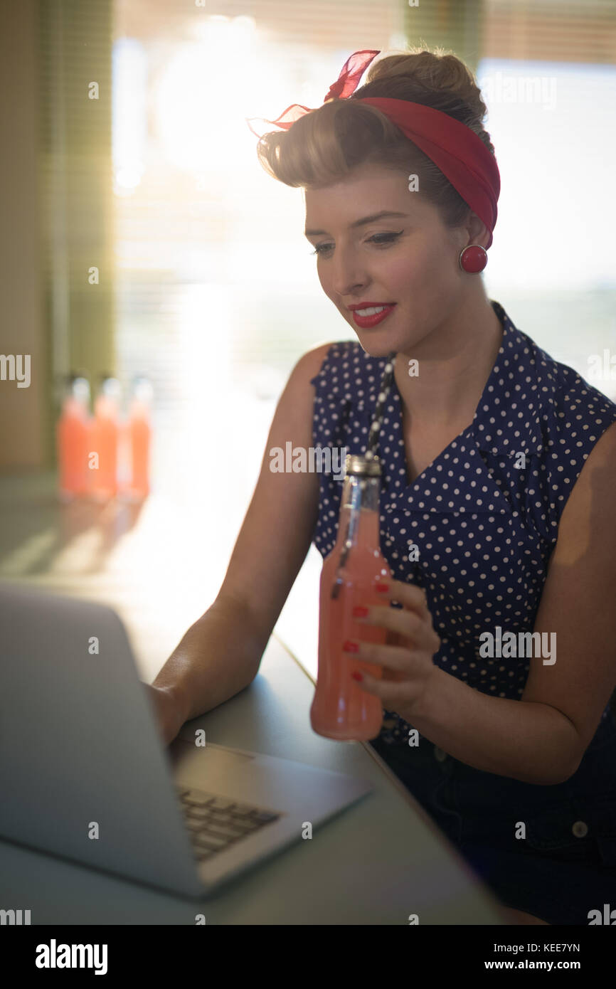 Beautiful woman using laptop while having drink in restaurant Stock ...