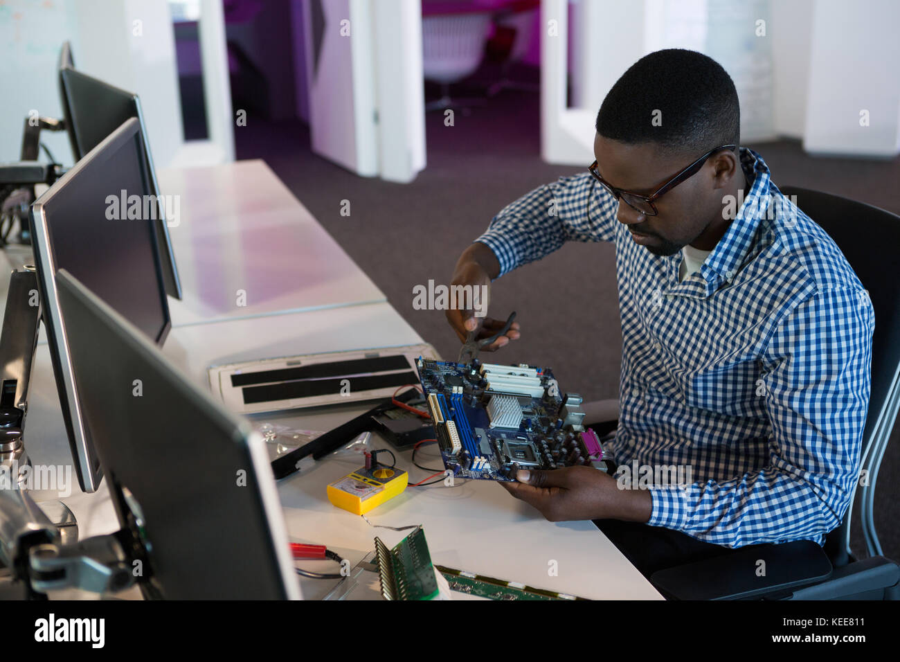 Computer engineer repairing motherboard at desk in office Stock Photo ...