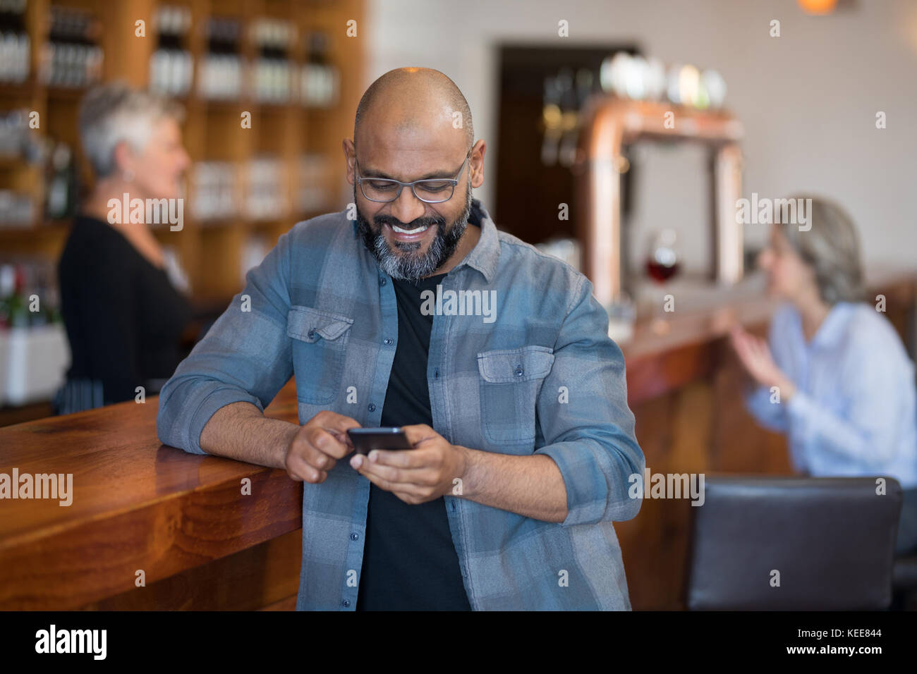 Smiling man using mobile phone at counter in bar Stock Photo - Alamy