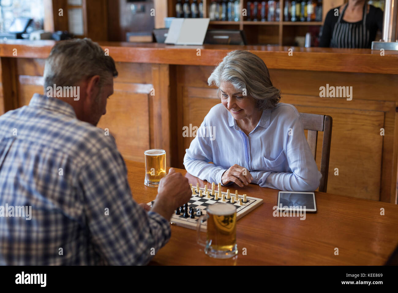 Smiling friends playing chess while having glass of beer in bar Stock ...