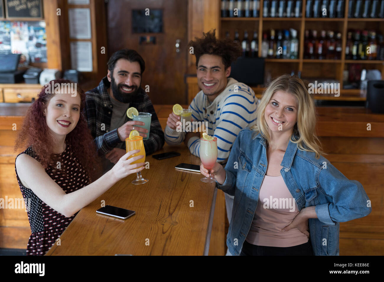 Smiling friends having glass of drinks at counter in bar Stock Photo ...