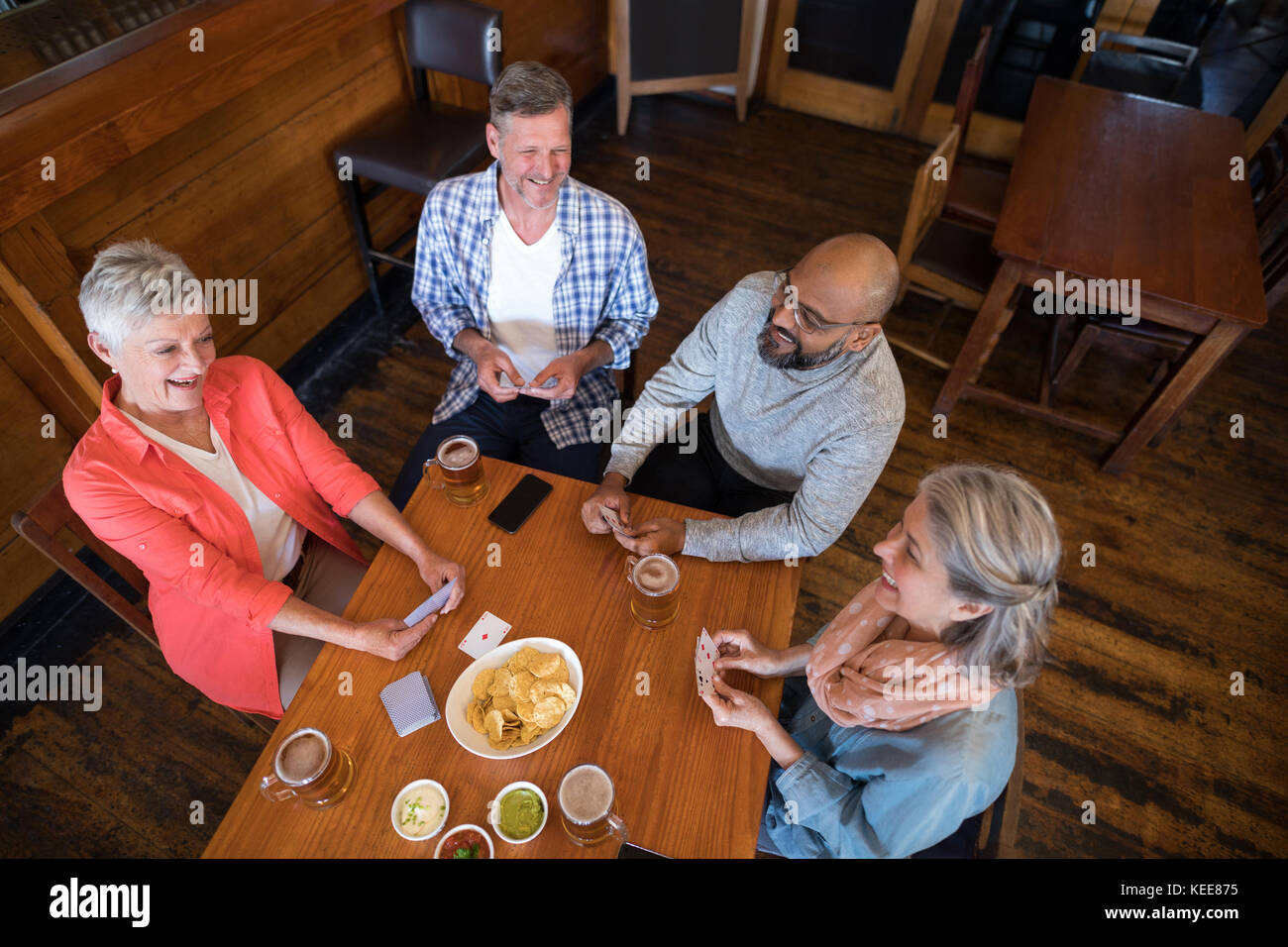 Happy friends playing cards while having beer and snacks in bar Stock ...