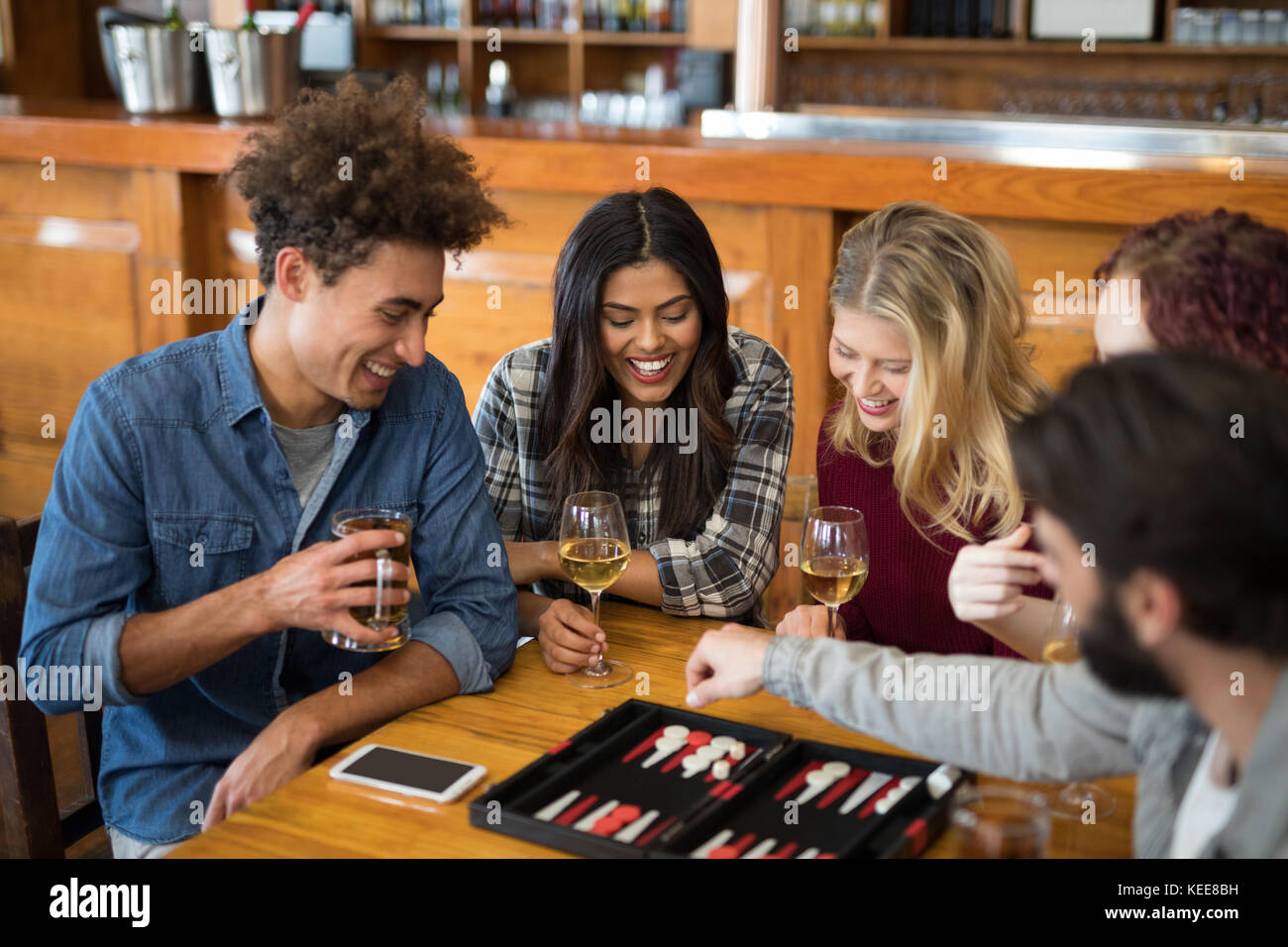 Happy friends playing backgammon while having drinks in bar Stock Photo ...