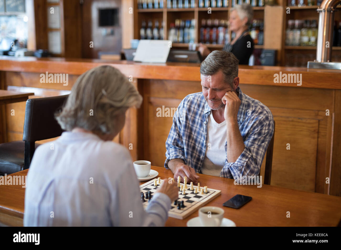 Friends playing chess while having coffee in bar Stock Photo - Alamy